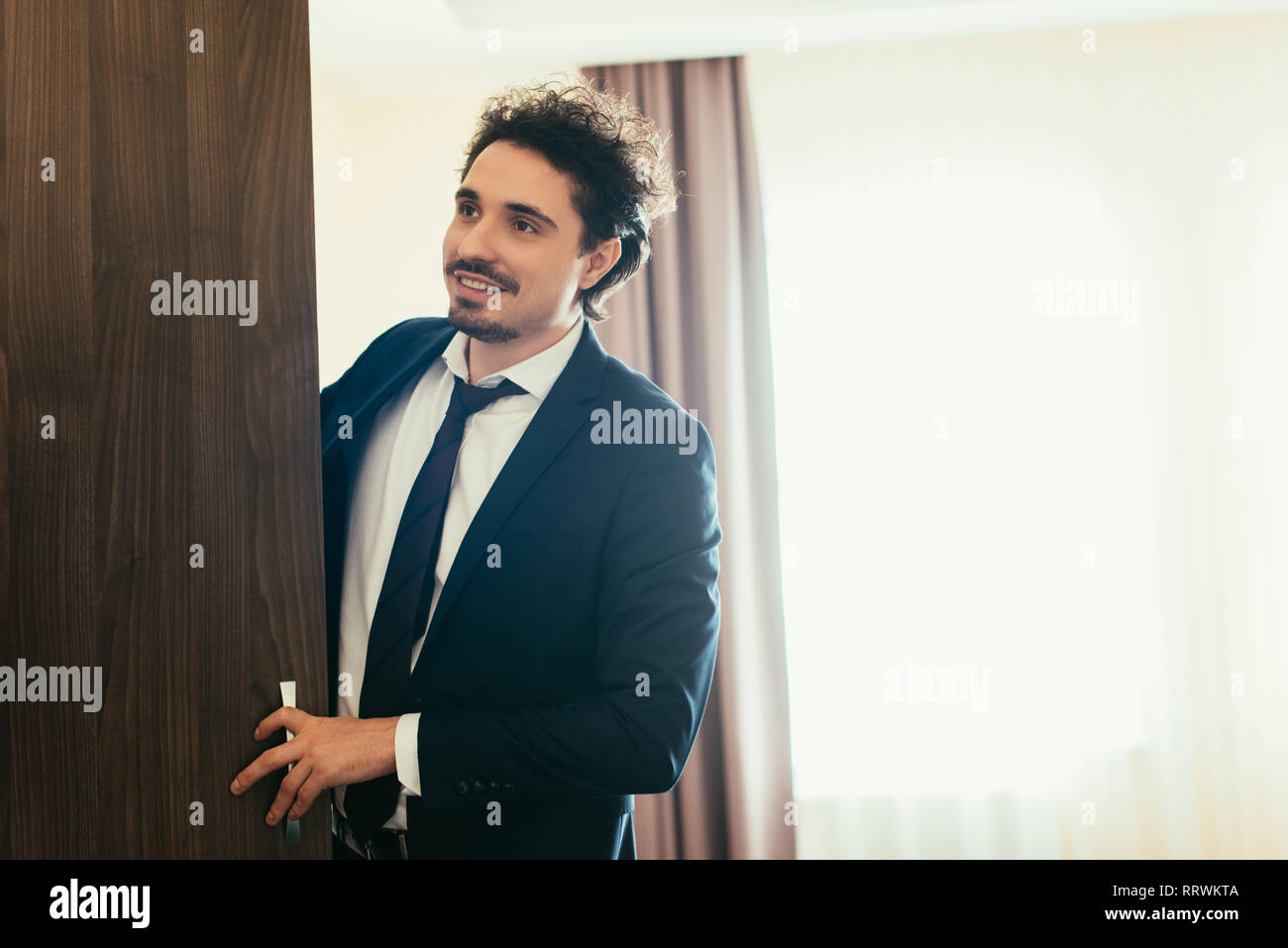 handsome smiling businessman opening wardrobe in hotel room Stock Photo ...