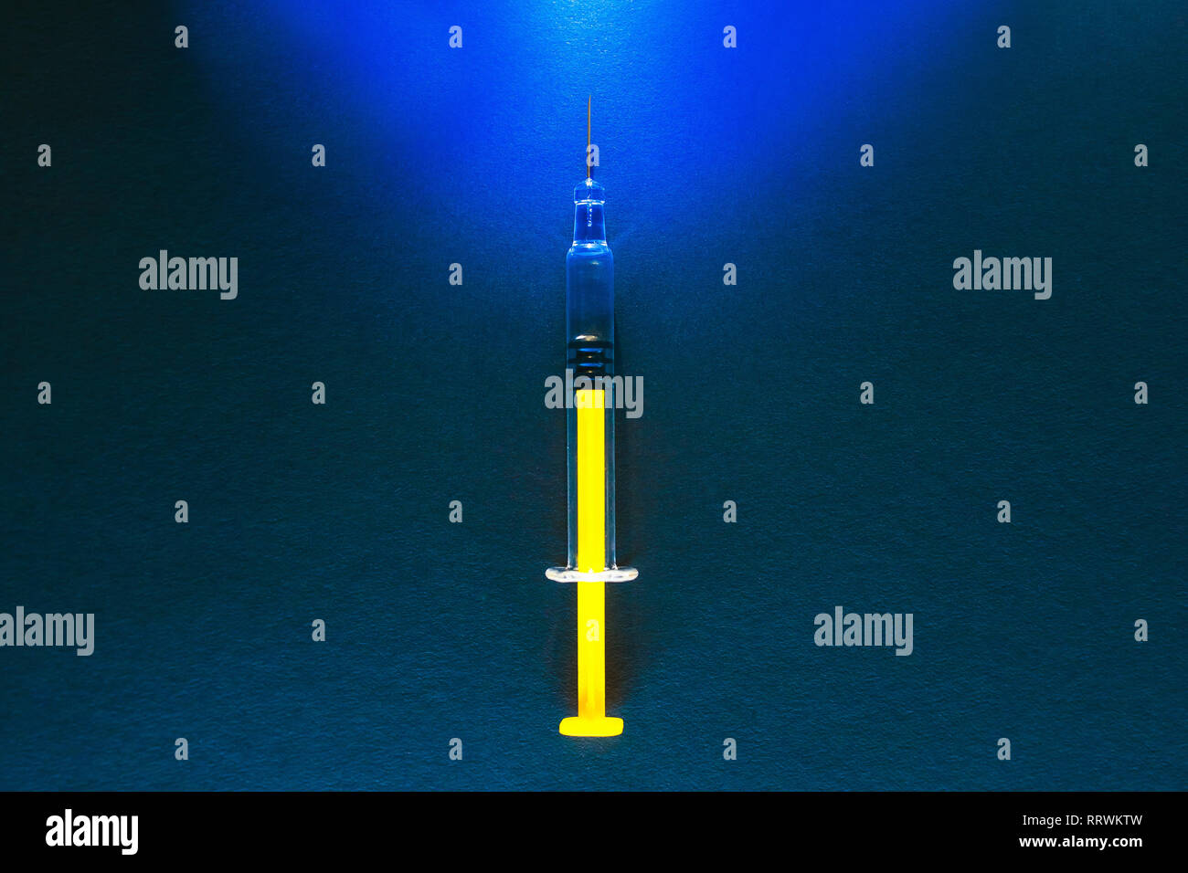 Yellow glass medical syringe over dark background Stock Photo - Alamy