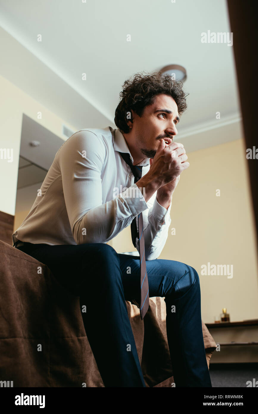 worried businessman in formal wear talking on smartphone in hotel room ...