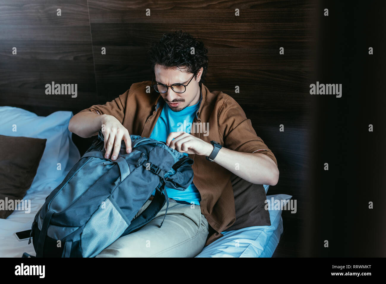 male tourist looking into backpack in hotel room Stock Photo - Alamy