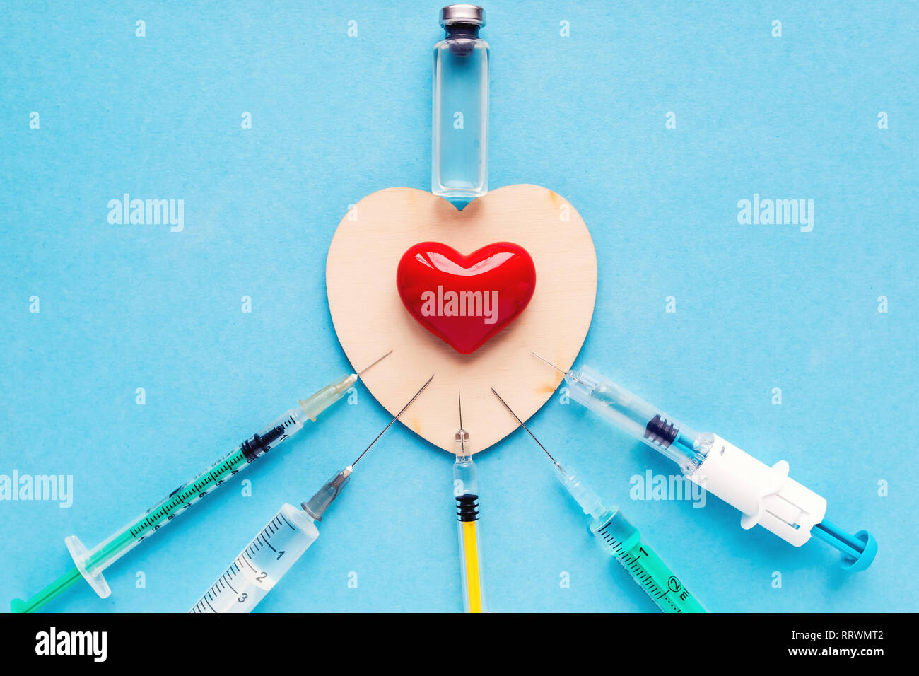 Volumetric heart shape with a set of different syringes on a blue ...