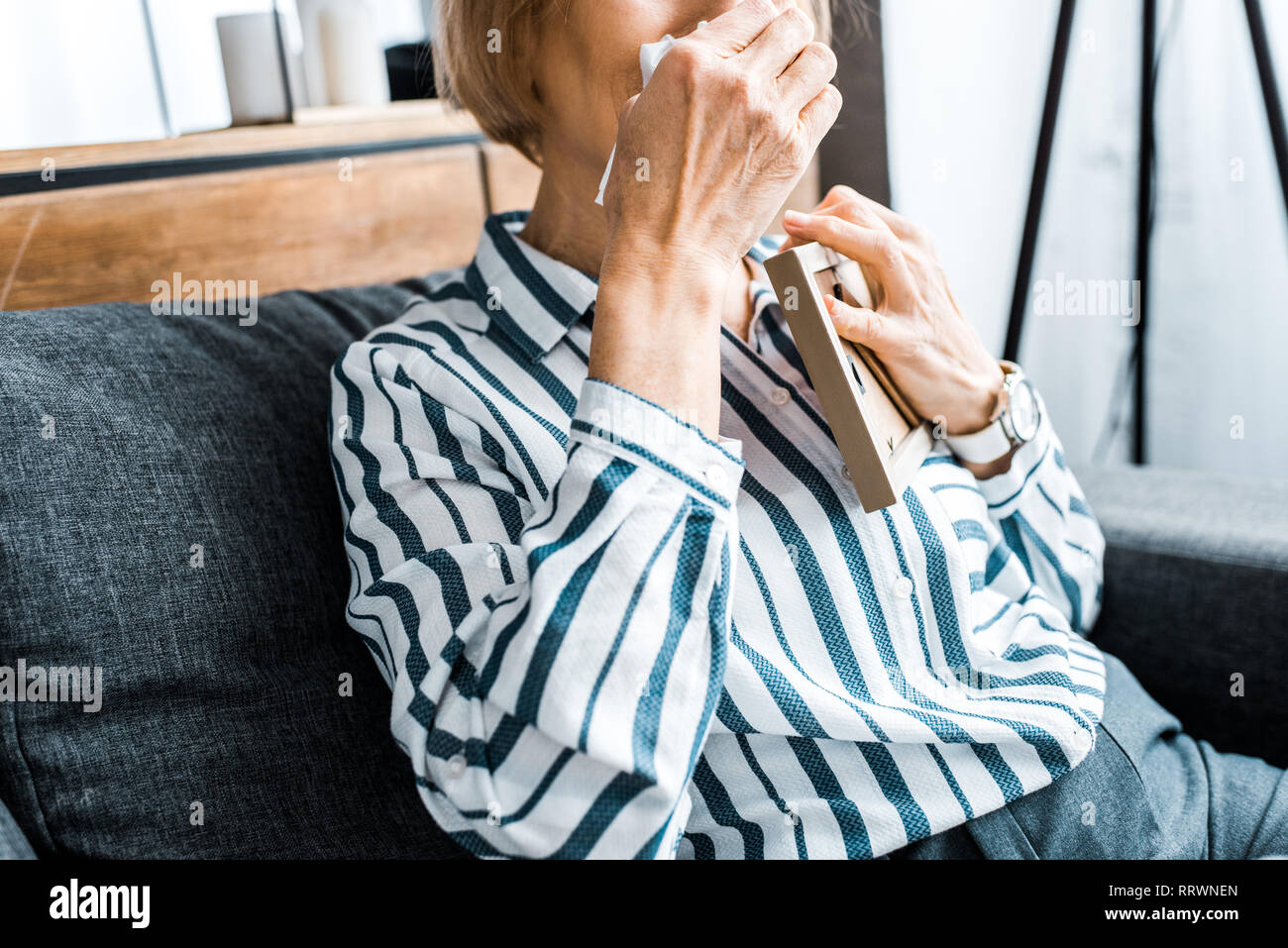 cropped view of senior woman wiping face from tears with tissue and ...