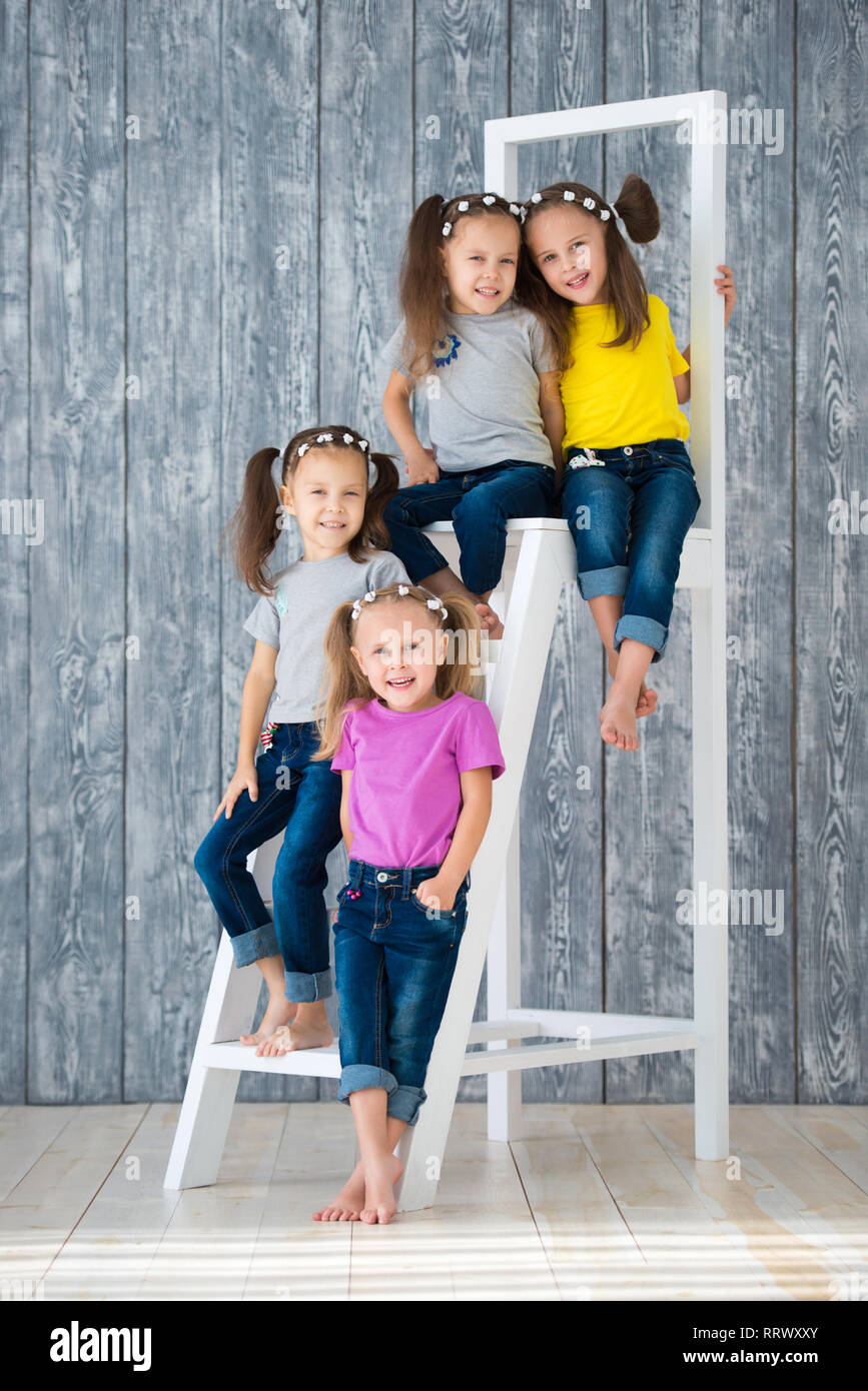 Four pretty cheerful girls triple twins sisters in jeans are sitting on ...