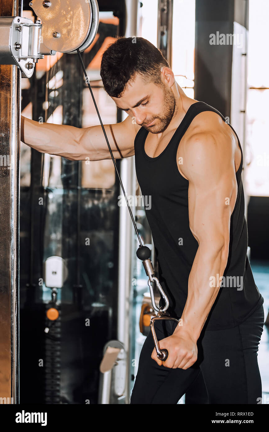 Muscular man working out in gym doing exercises at triceps, strong male ...