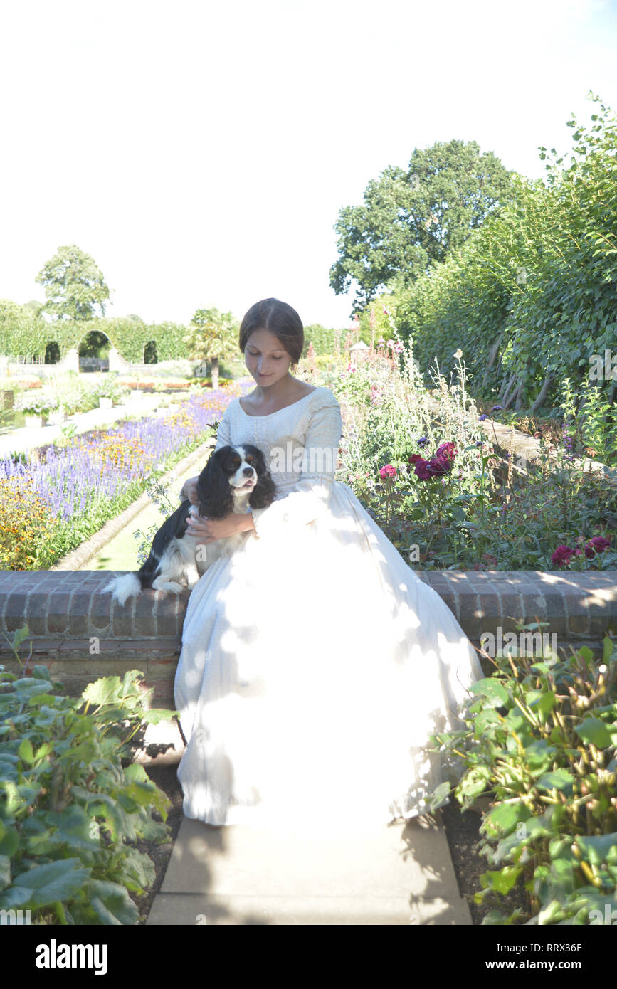 A young Queen Victoria and her dog Dash sit on a wall in the garden at ...