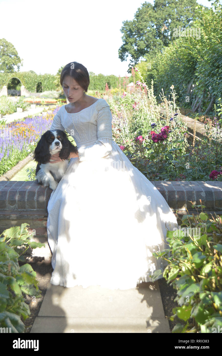 A young Queen Victoria and her dog Dash sit on a wall in the garden at ...