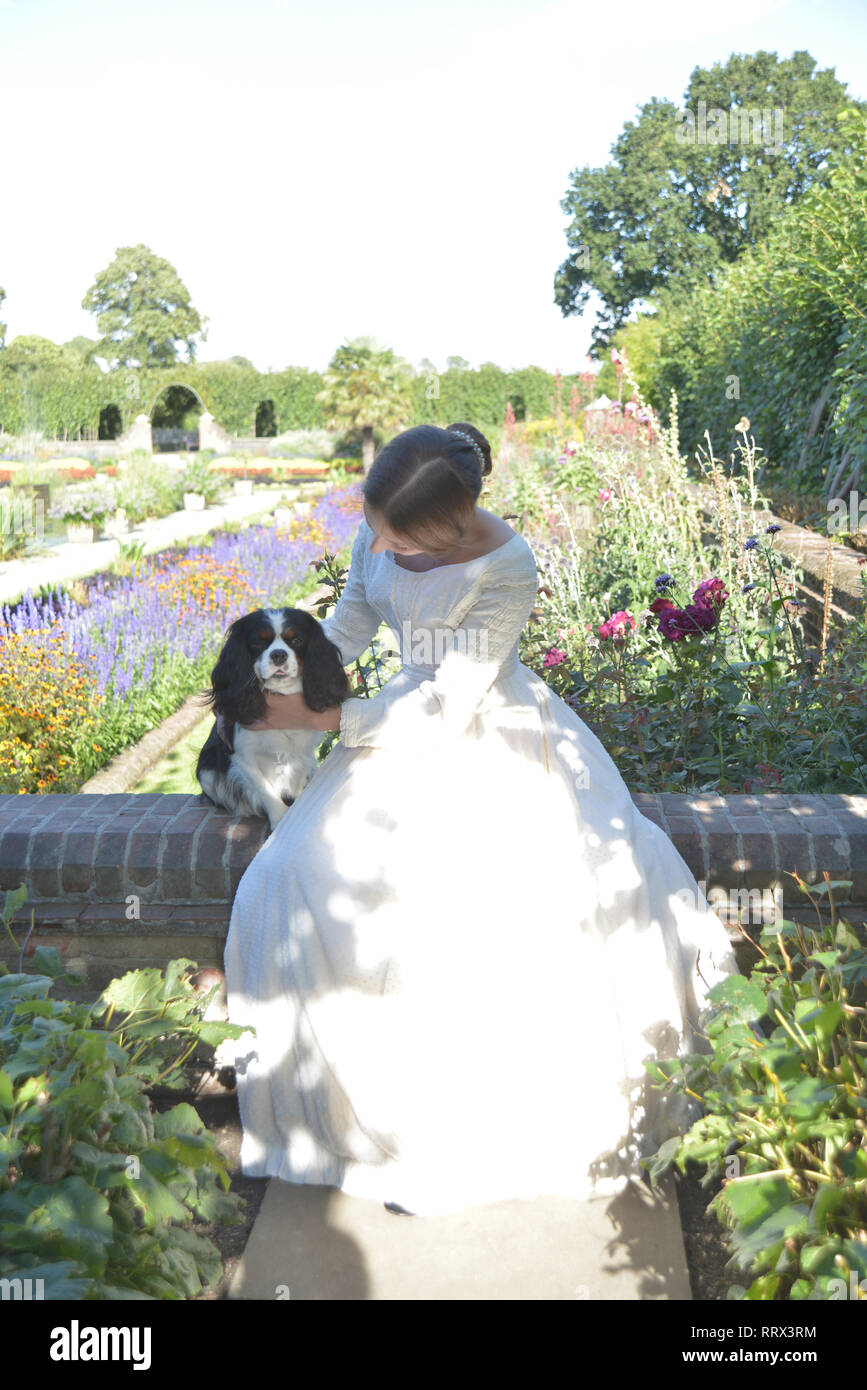 A young Queen Victoria and her dog Dash sit on a wall in the garden at ...