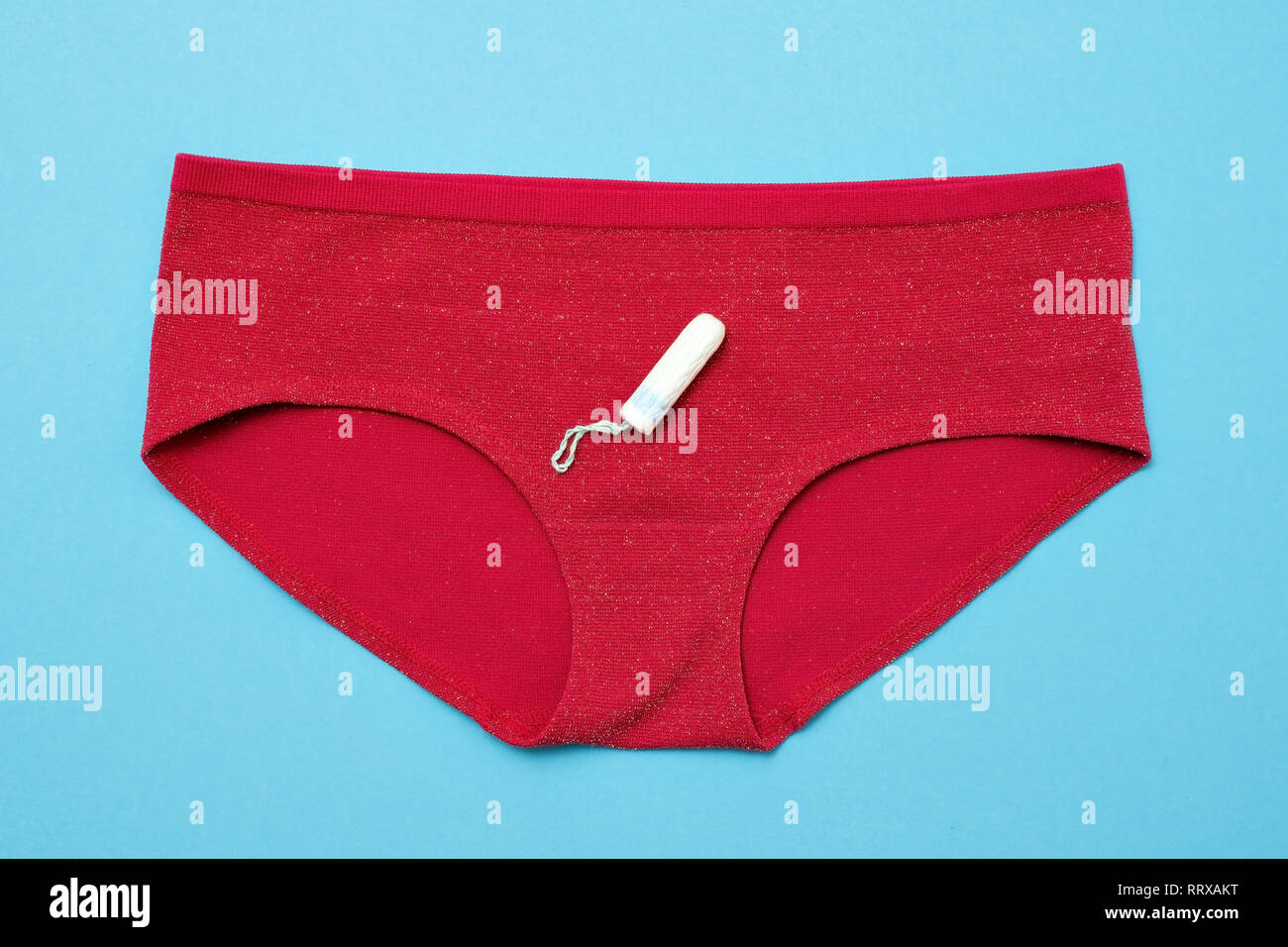 White Tampon On Red Pants On Colored Background Concept Of Woman Hygiene During Menstruation