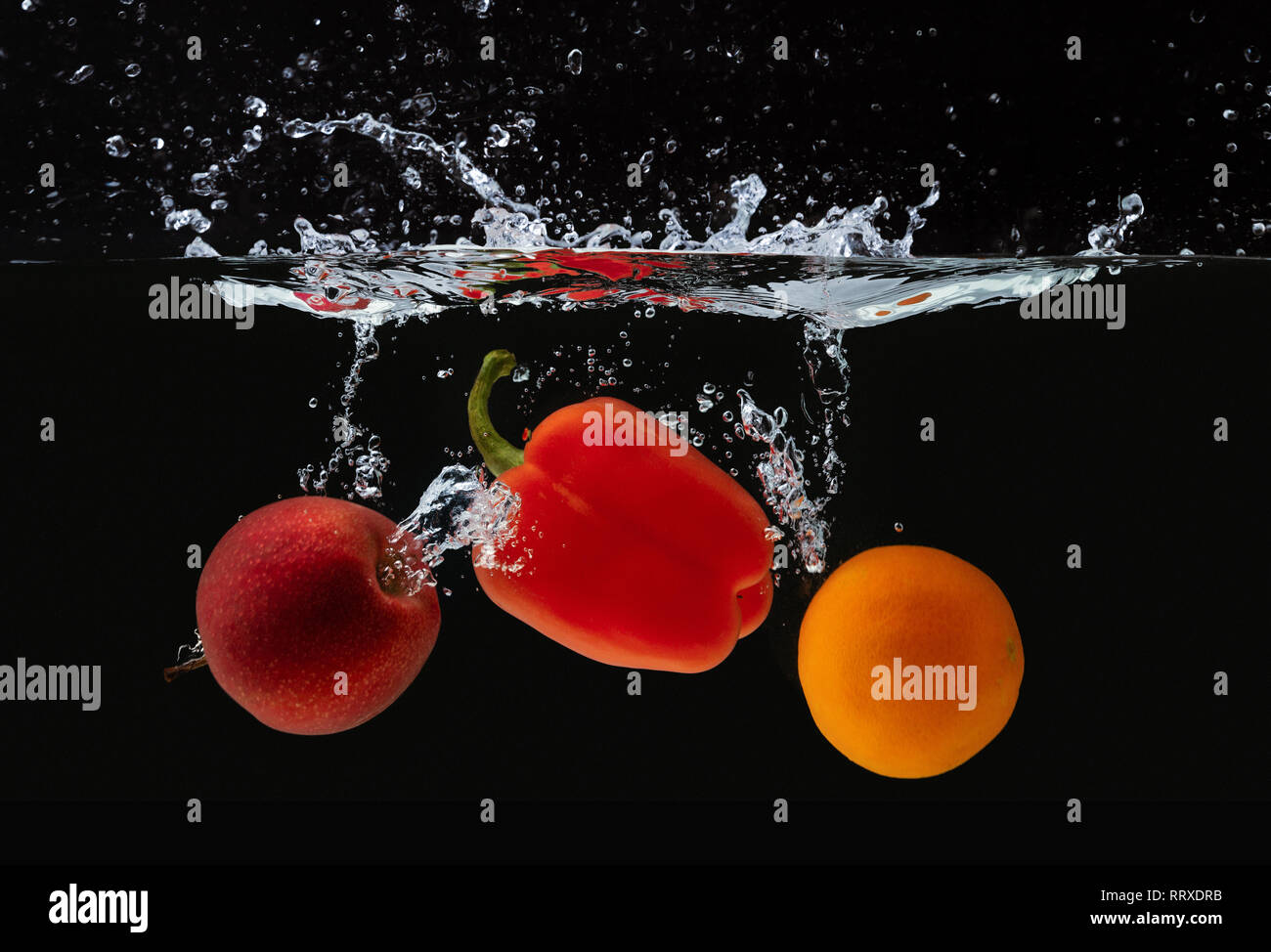 Fresh apple, orange and pepper water splash on black Stock Photo - Alamy