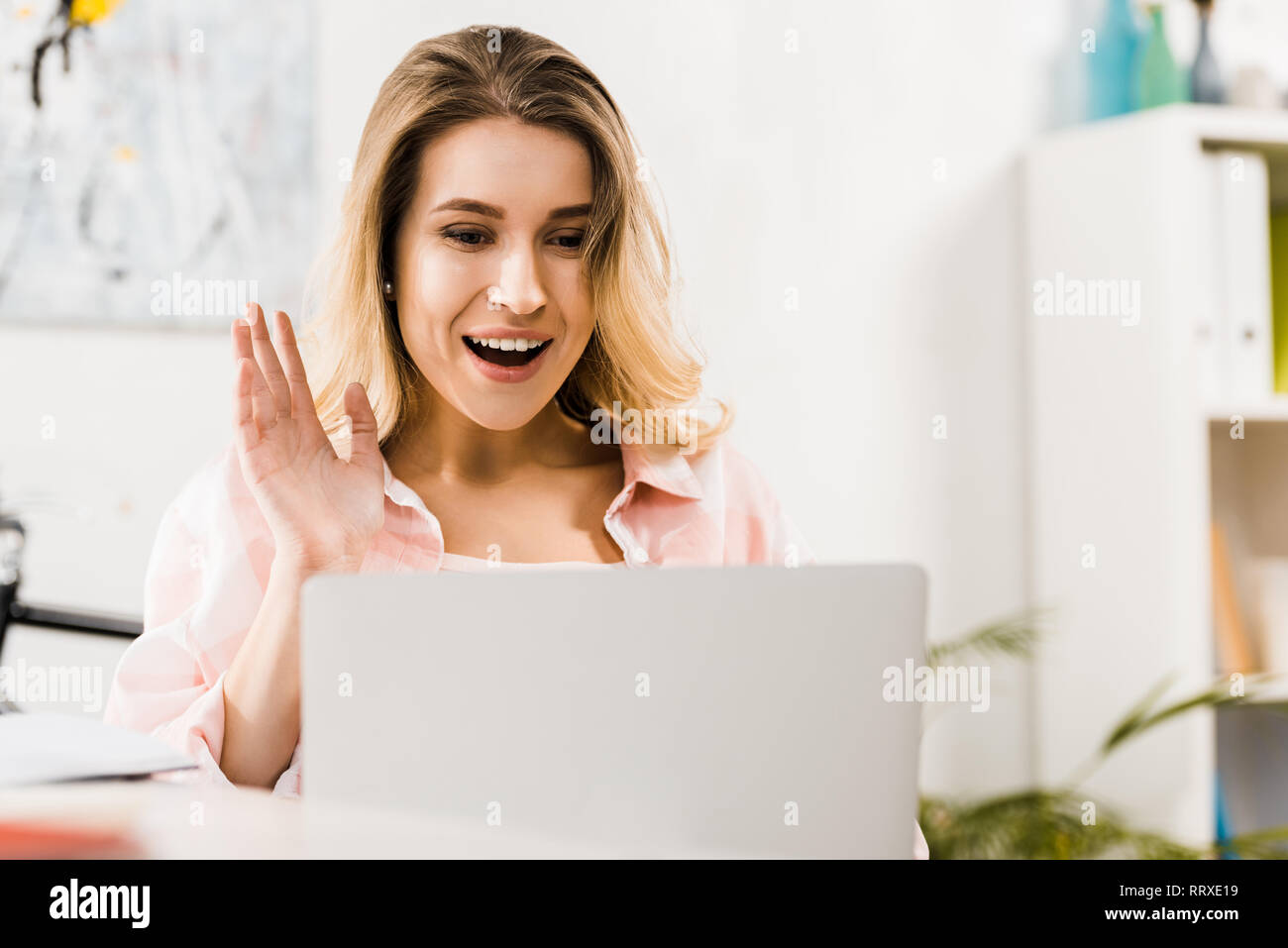 Excited girl looking at laptop screen and waving hand Stock Photo - Alamy