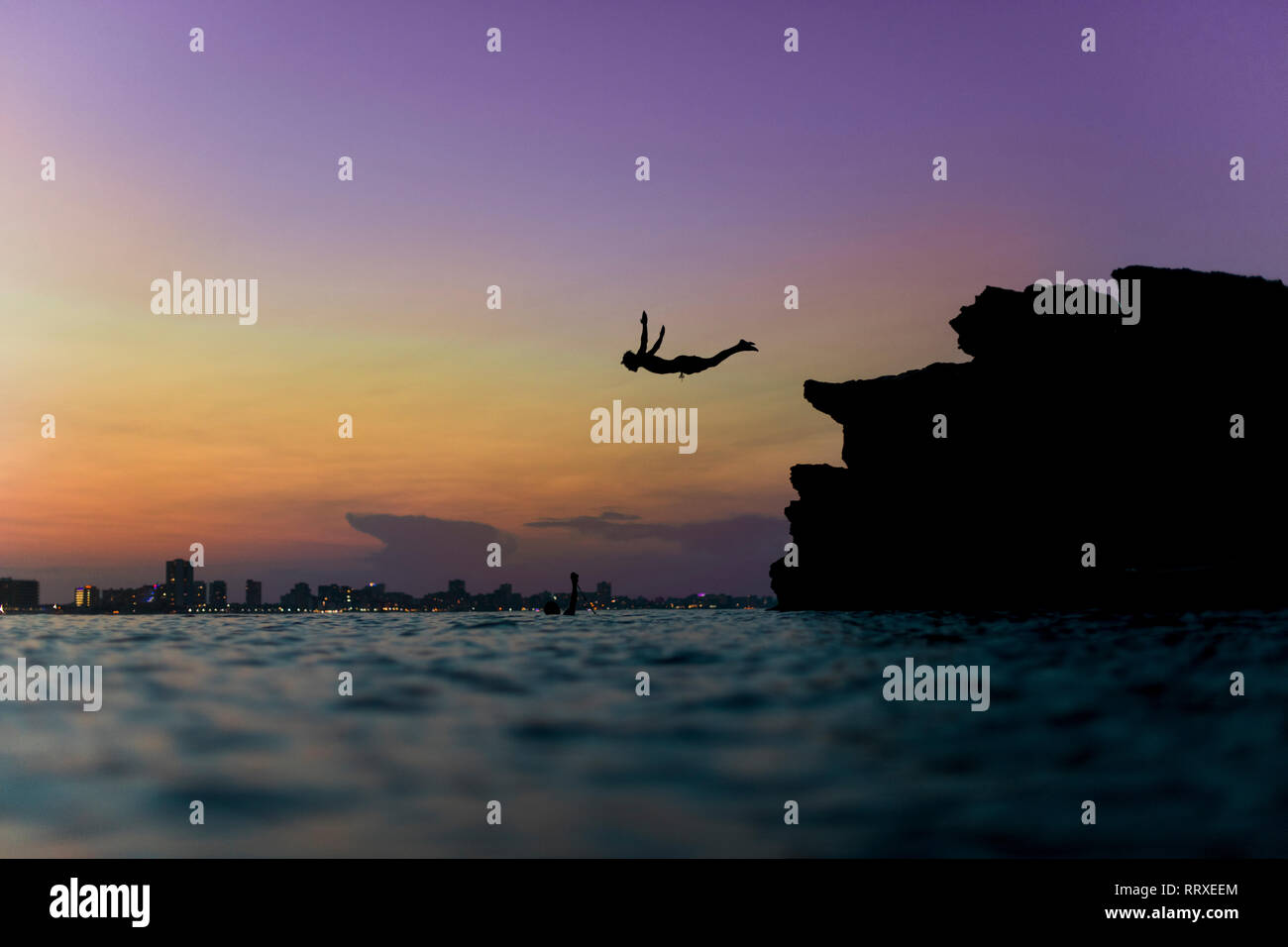 Side view of silhouette of person diving into ocean water from the ...