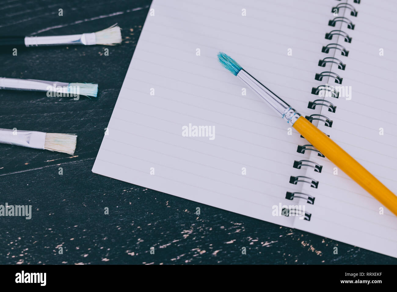 desk with notepads and watercolour brushes with empty pages and ...