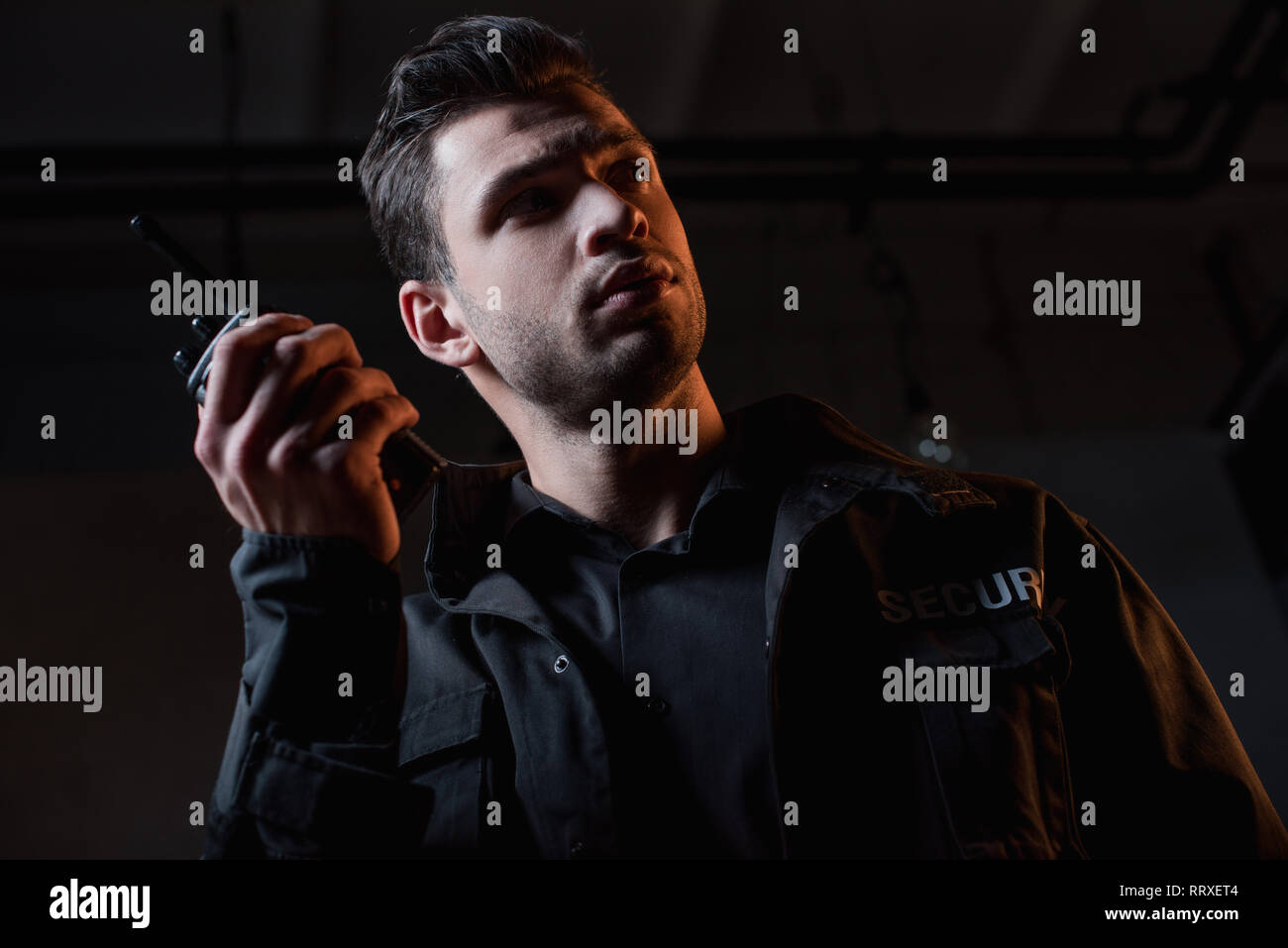 handsome guard in uniform holding walkie-talkie and looking away Stock ...