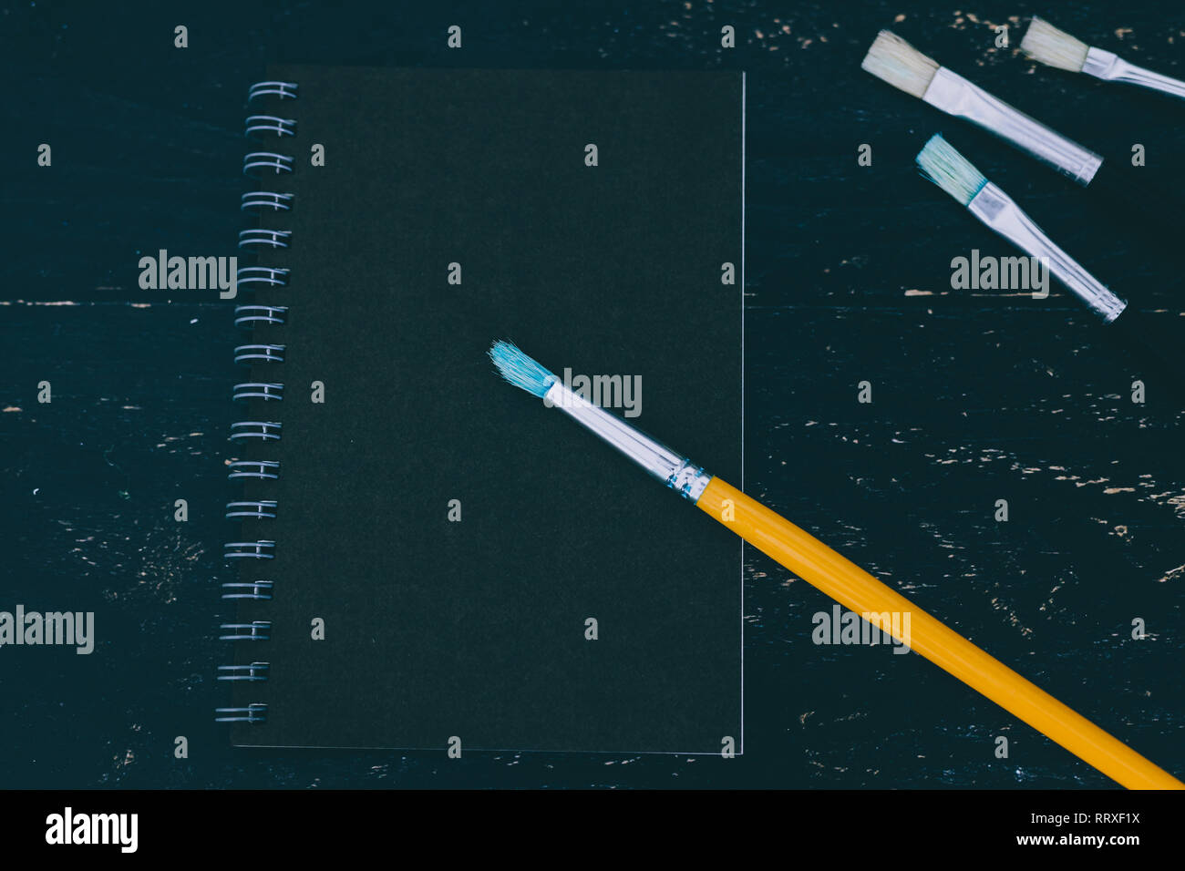 black desk with black notepad and watercolour brushes, concept of ...