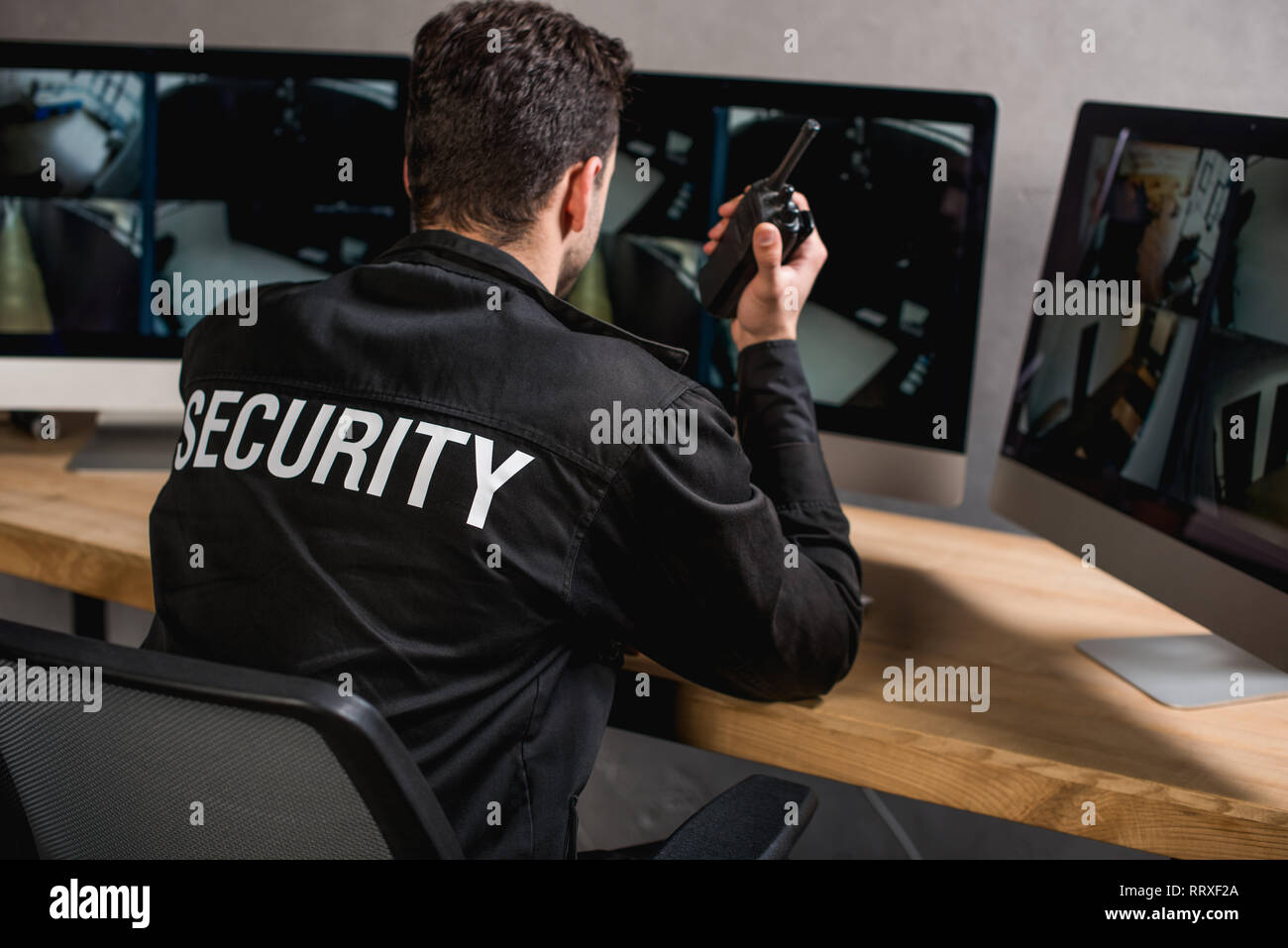 rear view of guard in uniform talking on walkie-talkie Stock Photo - Alamy
