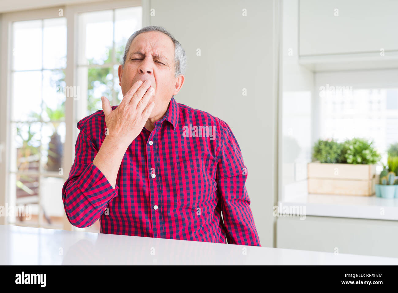 Handsome senior man at home bored yawning tired covering mouth with ...
