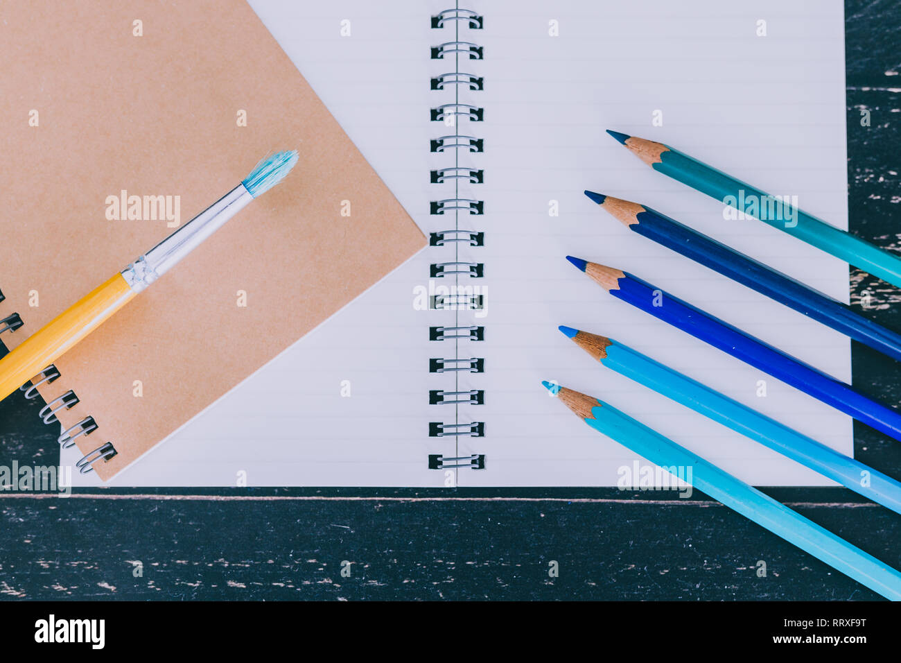 desk with notepads and watercolour brush and coloured pencils with ...