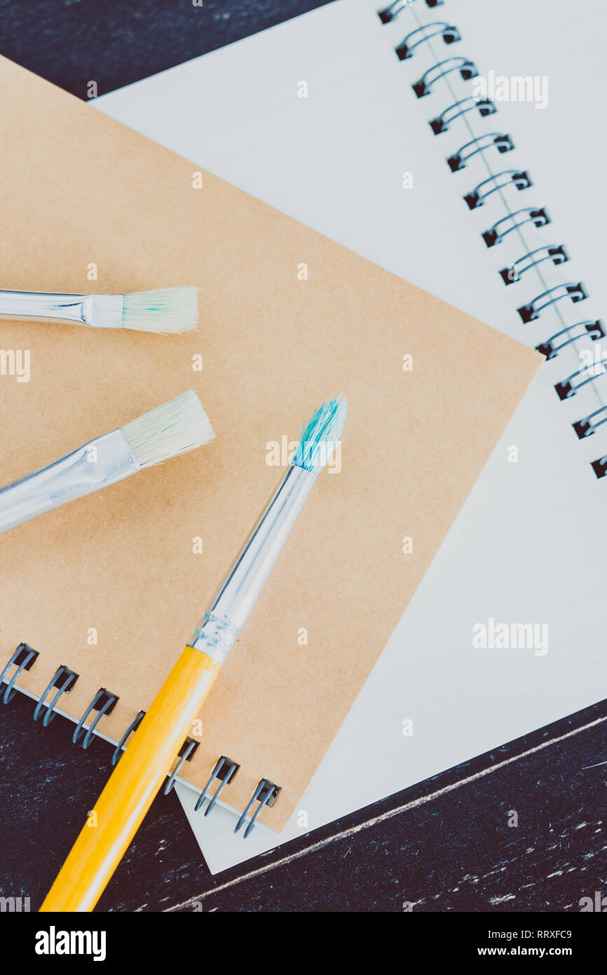 desk with notepads and watercolour brushes with empty pages and ...