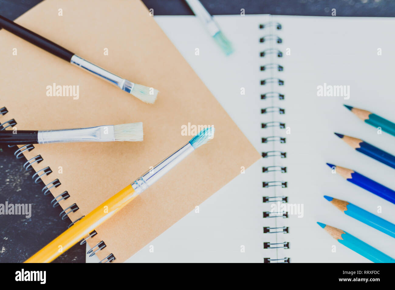 desk with notepads and watercolour brush and coloured pencils with ...