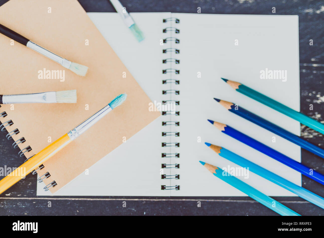 desk with notepads and watercolour brush and coloured pencils with ...