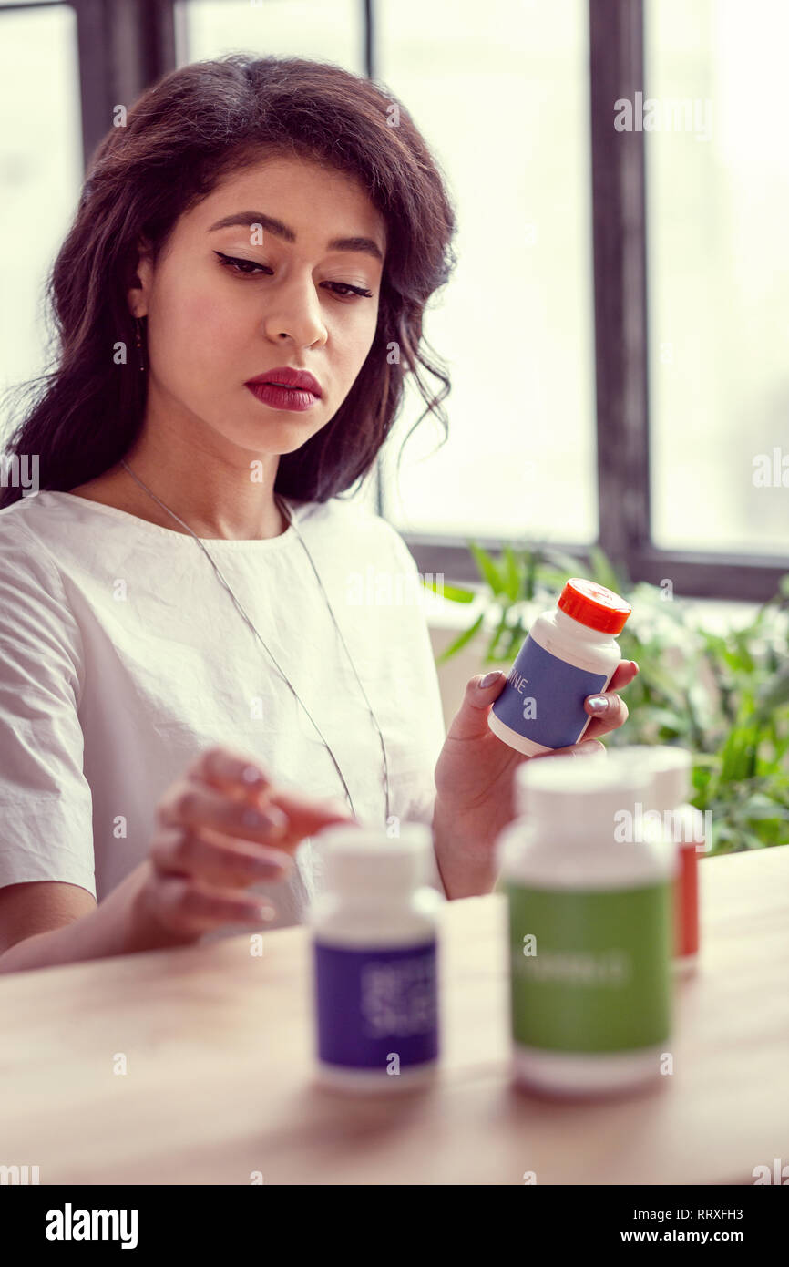 Smart good looking woman looking at her medicine Stock Photo - Alamy