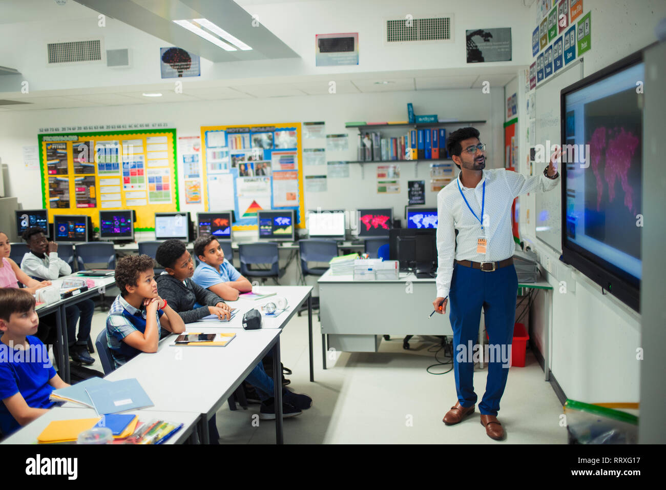 Male teacher leading lesson at touch screen in classroom Stock Photo ...