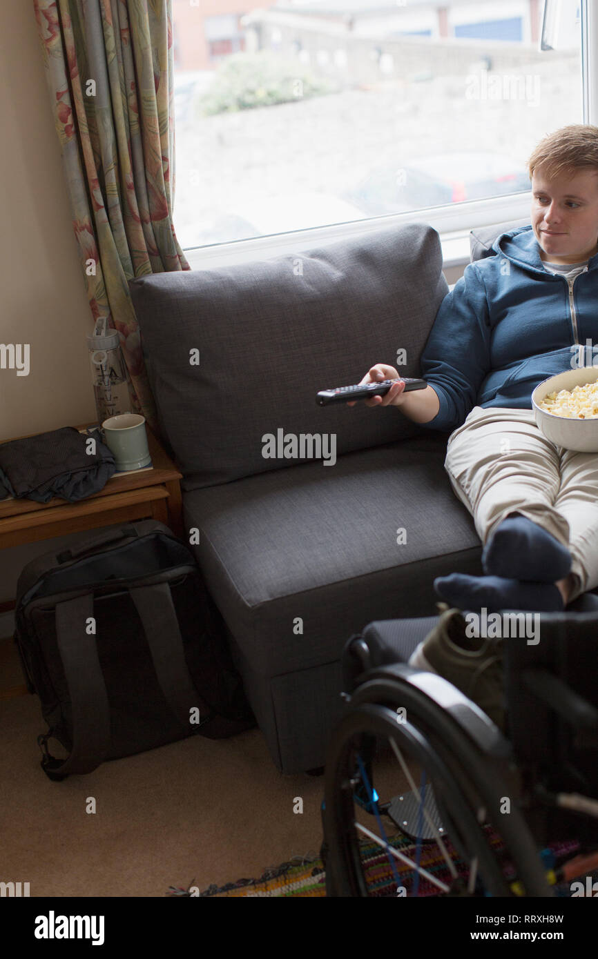 Young woman watching TV with feet up on wheelchair Stock Photo - Alamy