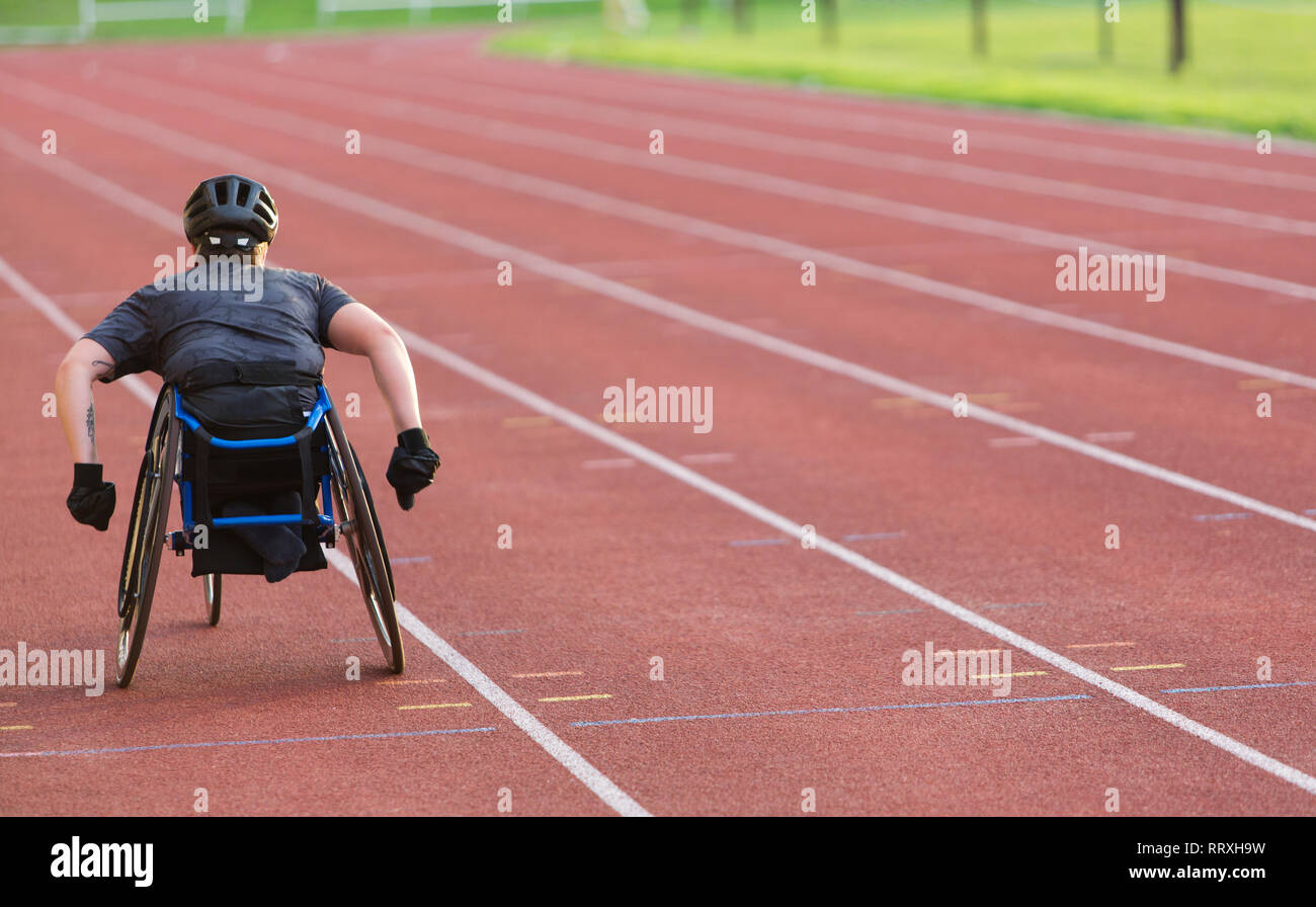 Female paraplegic athlete speeding along sports track in wheelchair ...