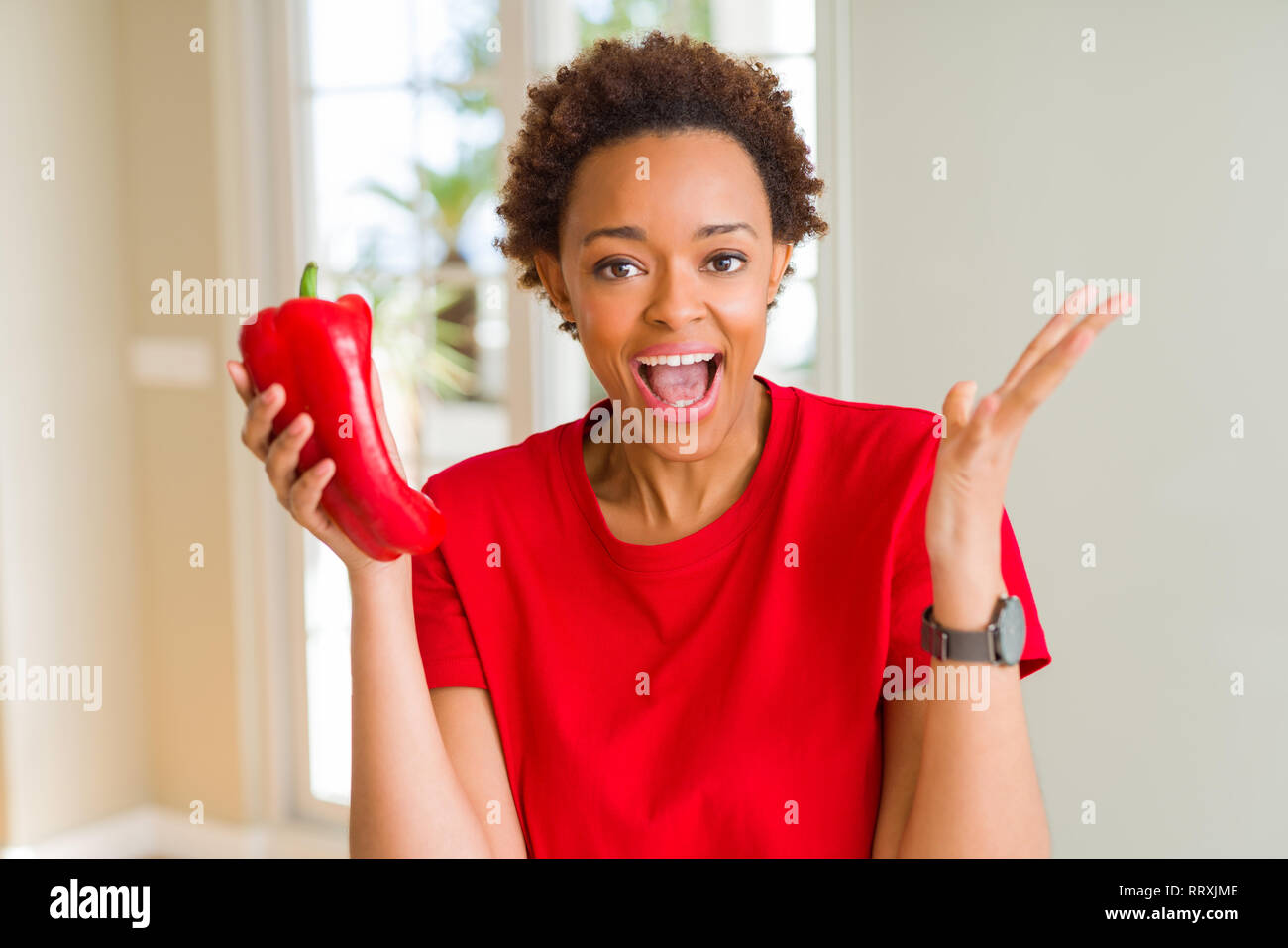 Young african american woman holding fresh red pepper very happy and ...