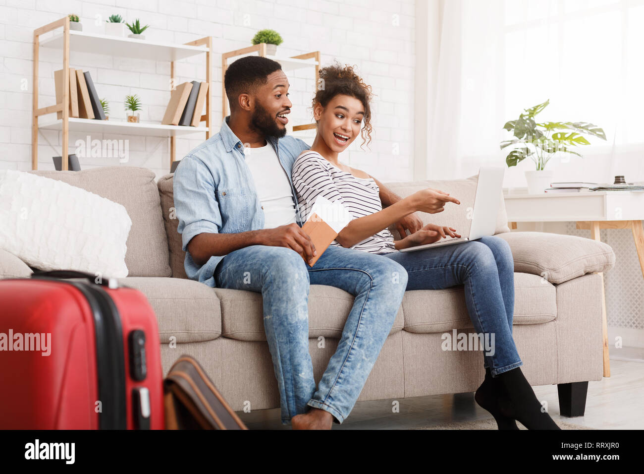 Happy couple searching places to visit using laptop Stock Photo - Alamy