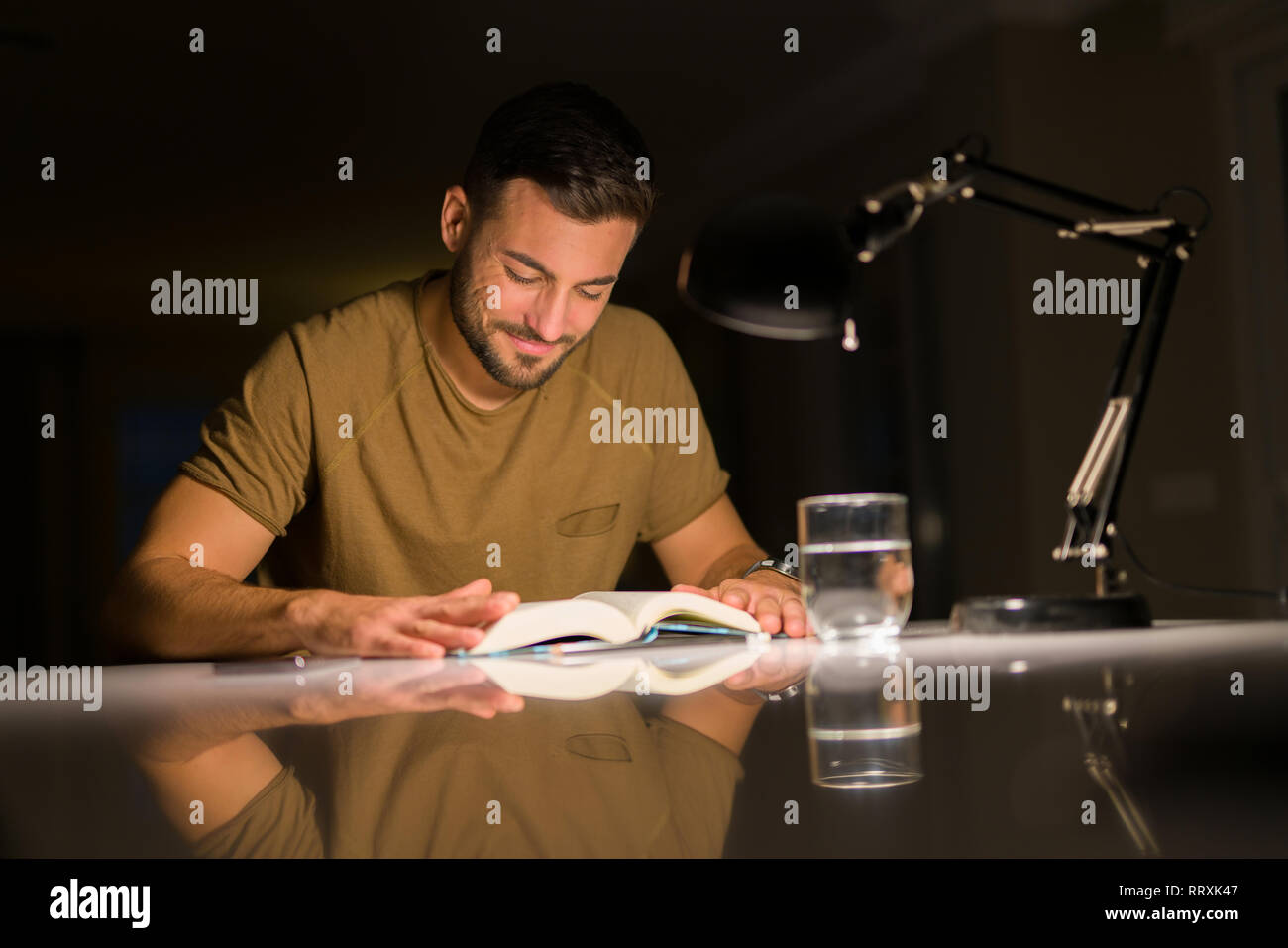 Young handsome man studying at home, reading a book at night Stock ...