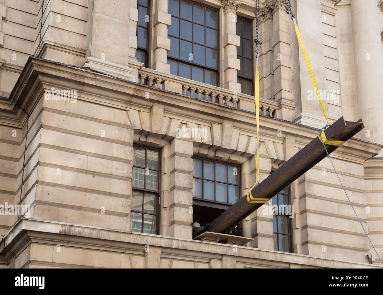 Bringing in a long steel beam through a window high up with the help of ...