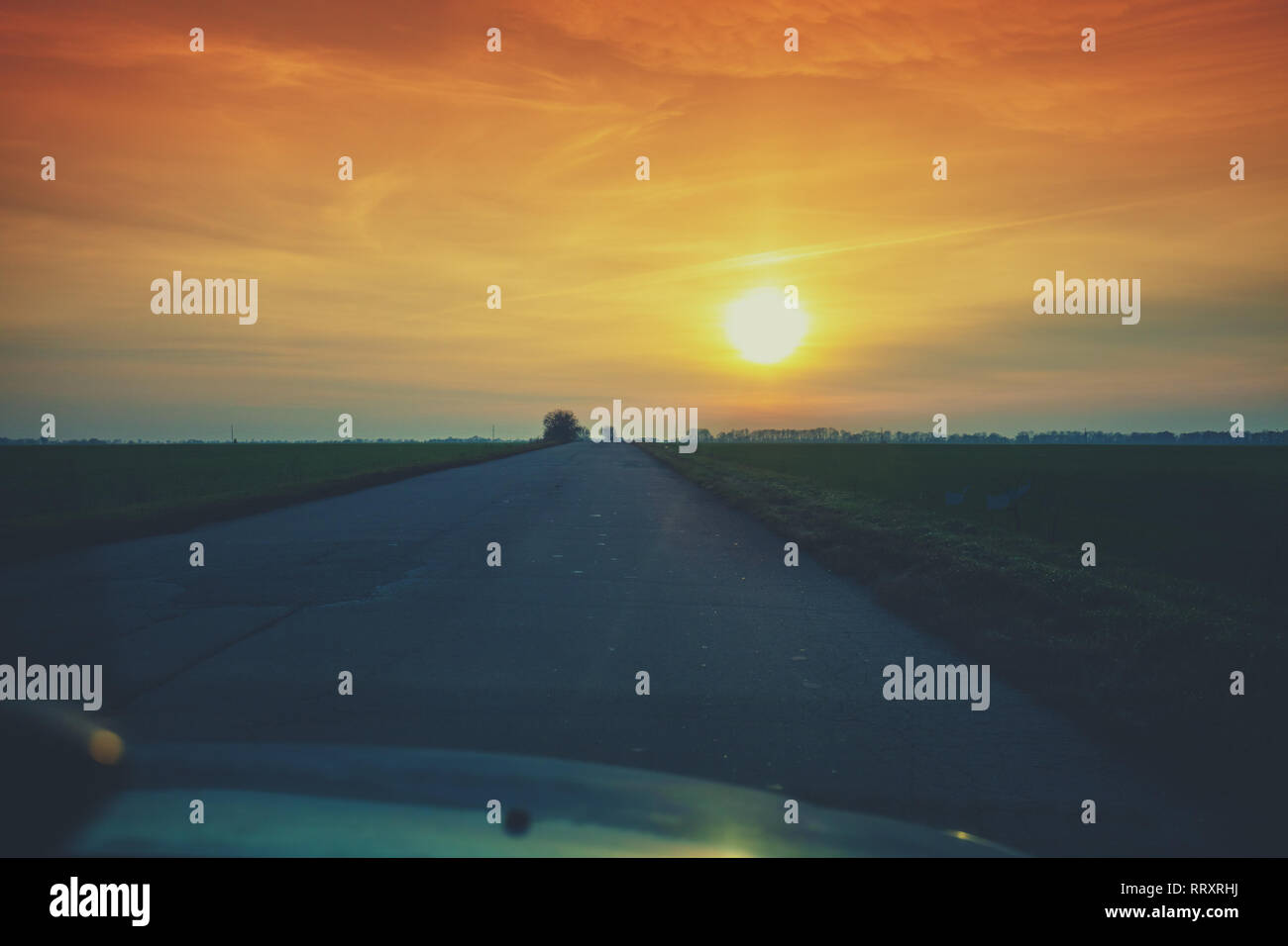 View through the windshield of a country road at sunset. Rural evening ...