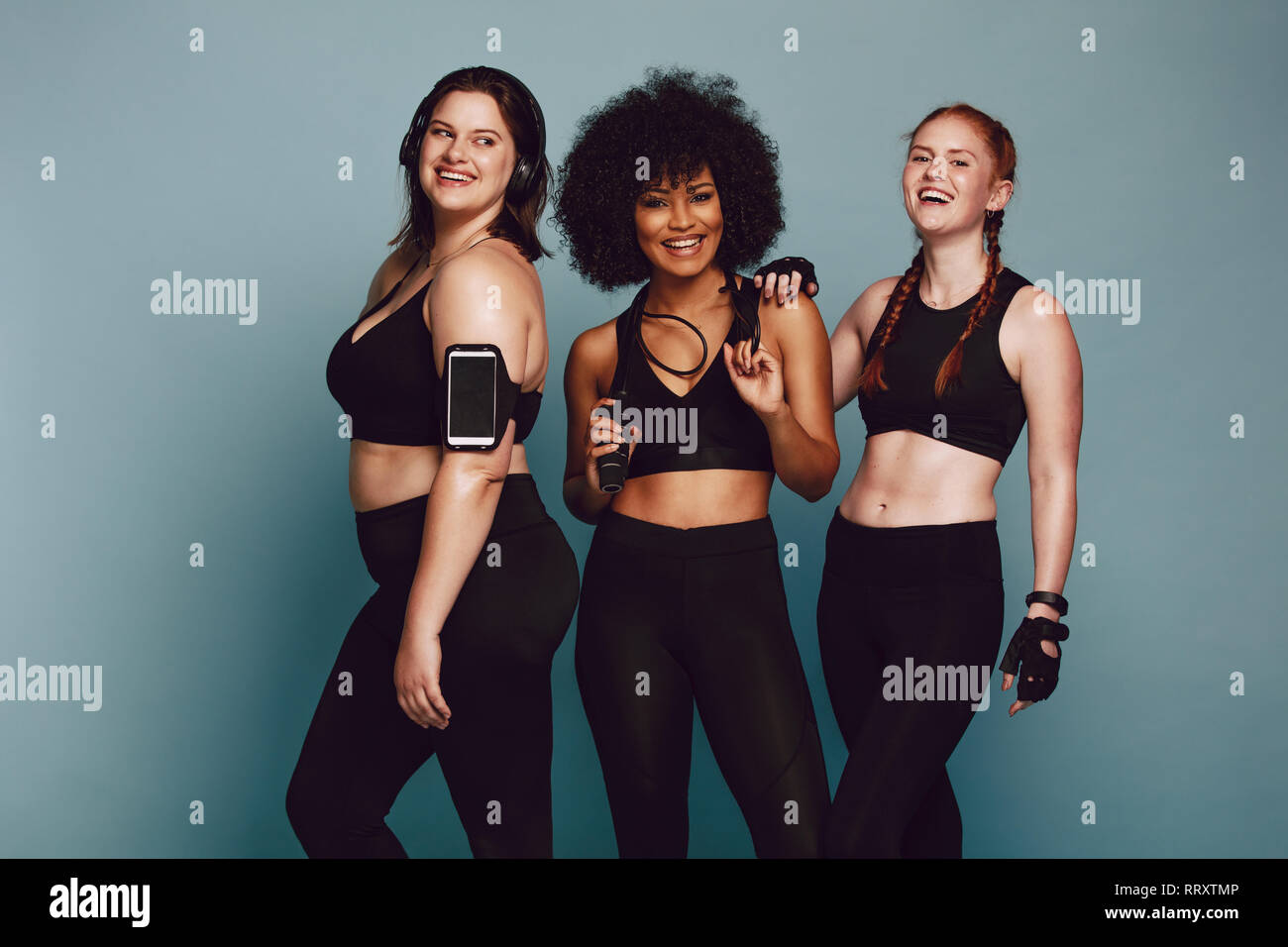 Portrait of mixed race women standing together against grey background ...