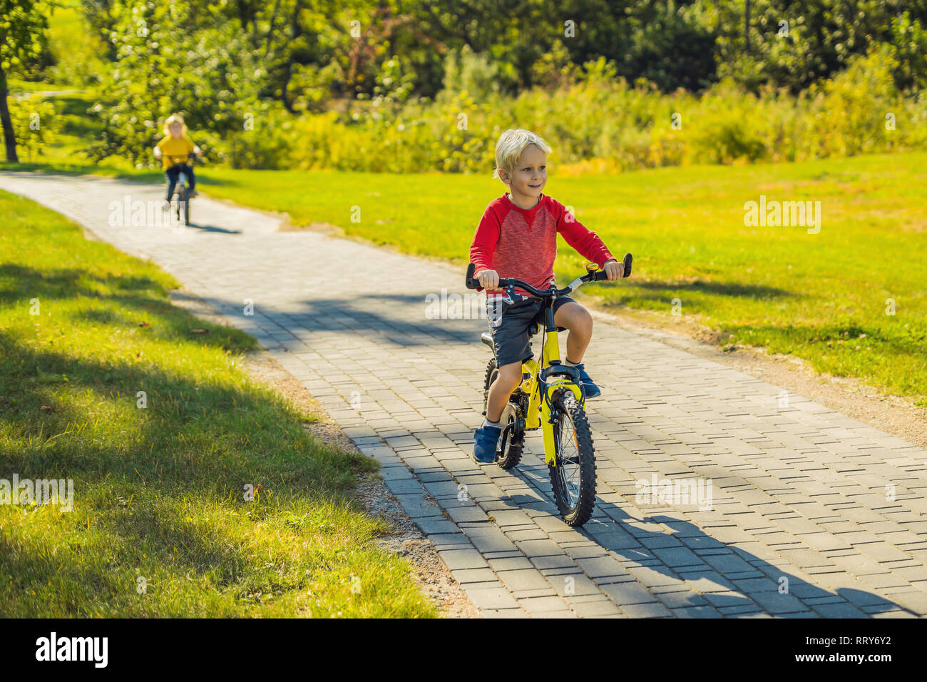 Two happy boys cycling in the park Stock Photo - Alamy