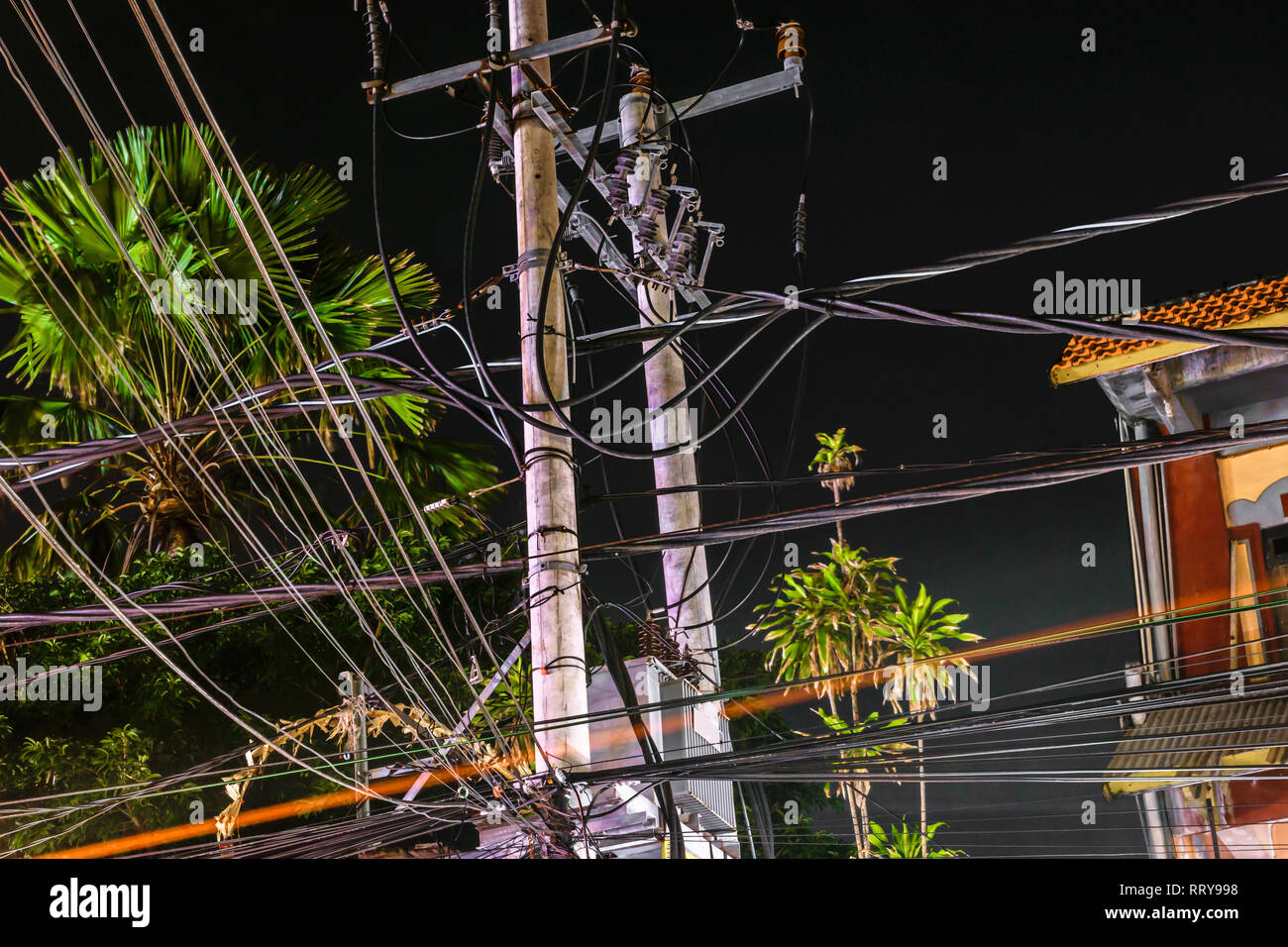 Night street view of bunch of wires connected on the pillars in Bali ...