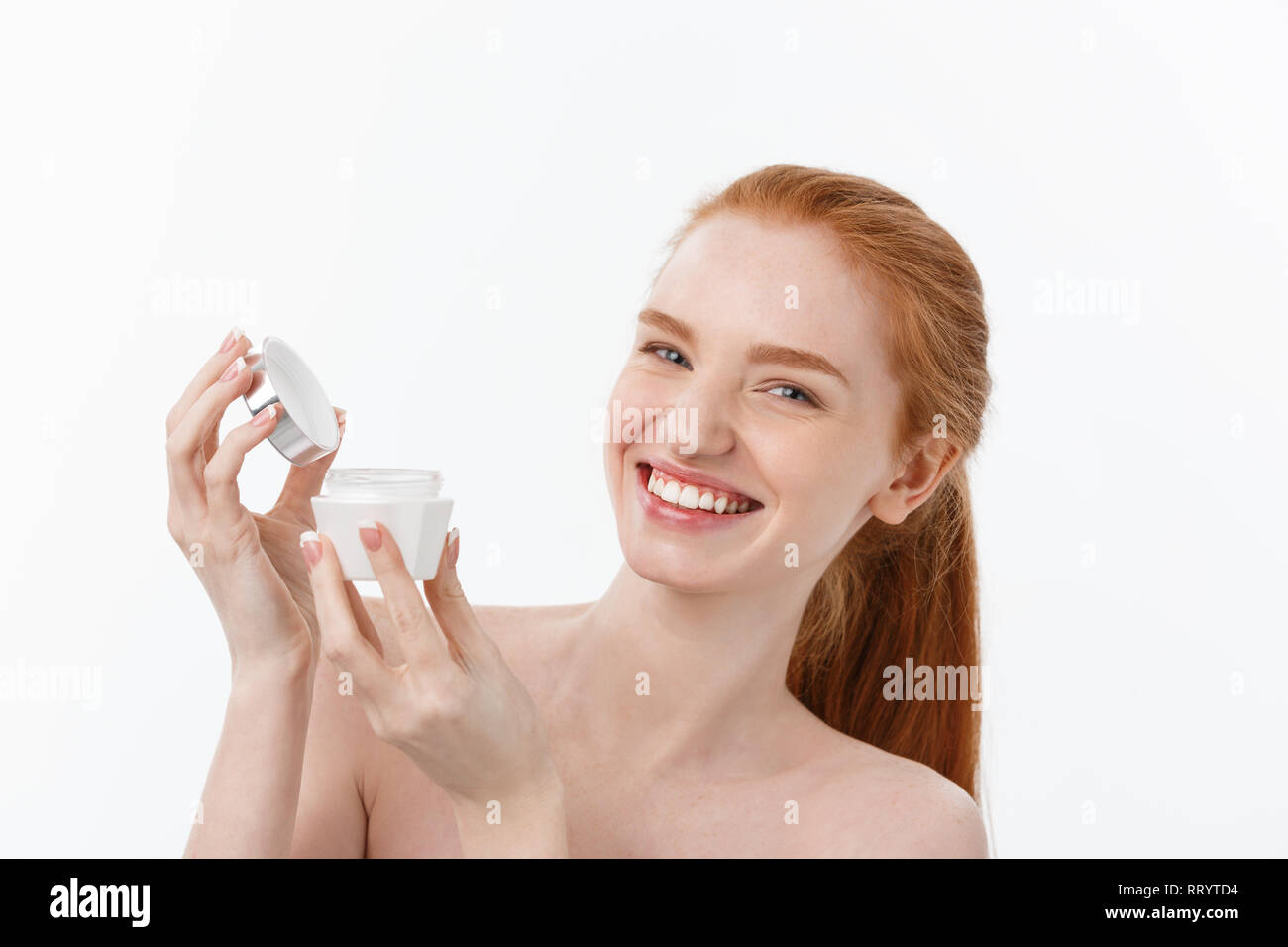 portrait of beautiful woman smiling while taking some facial cream ...