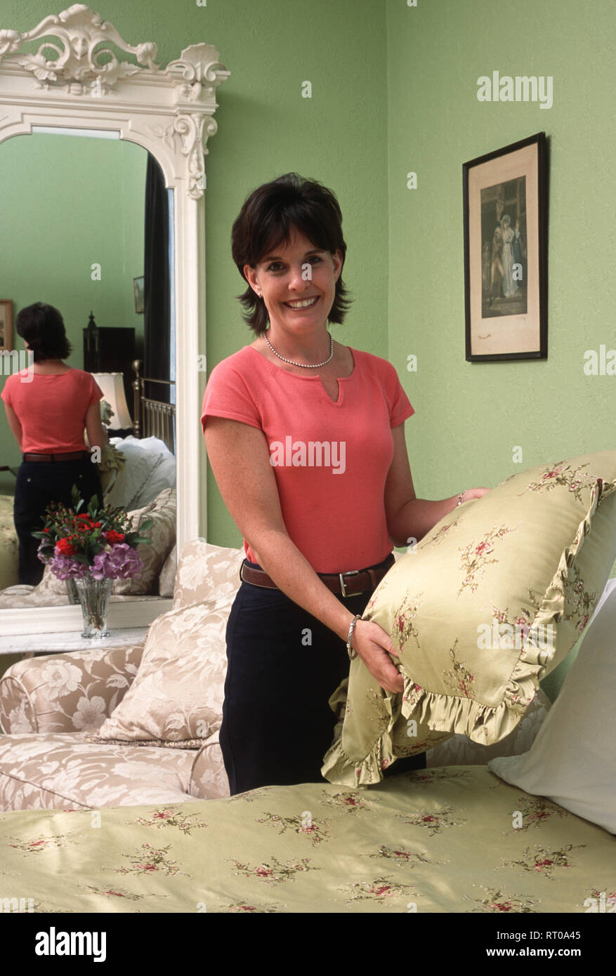 Pretty female innkeeper fluffs a guest bedroom pillow, Cooperstown, New ...