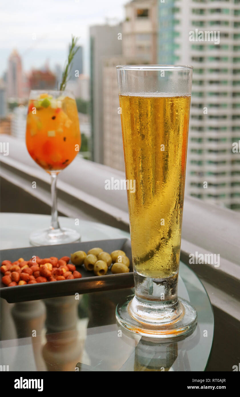 Glass of cold draft beer with blurry fresh fruits Sangria cocktail on ...