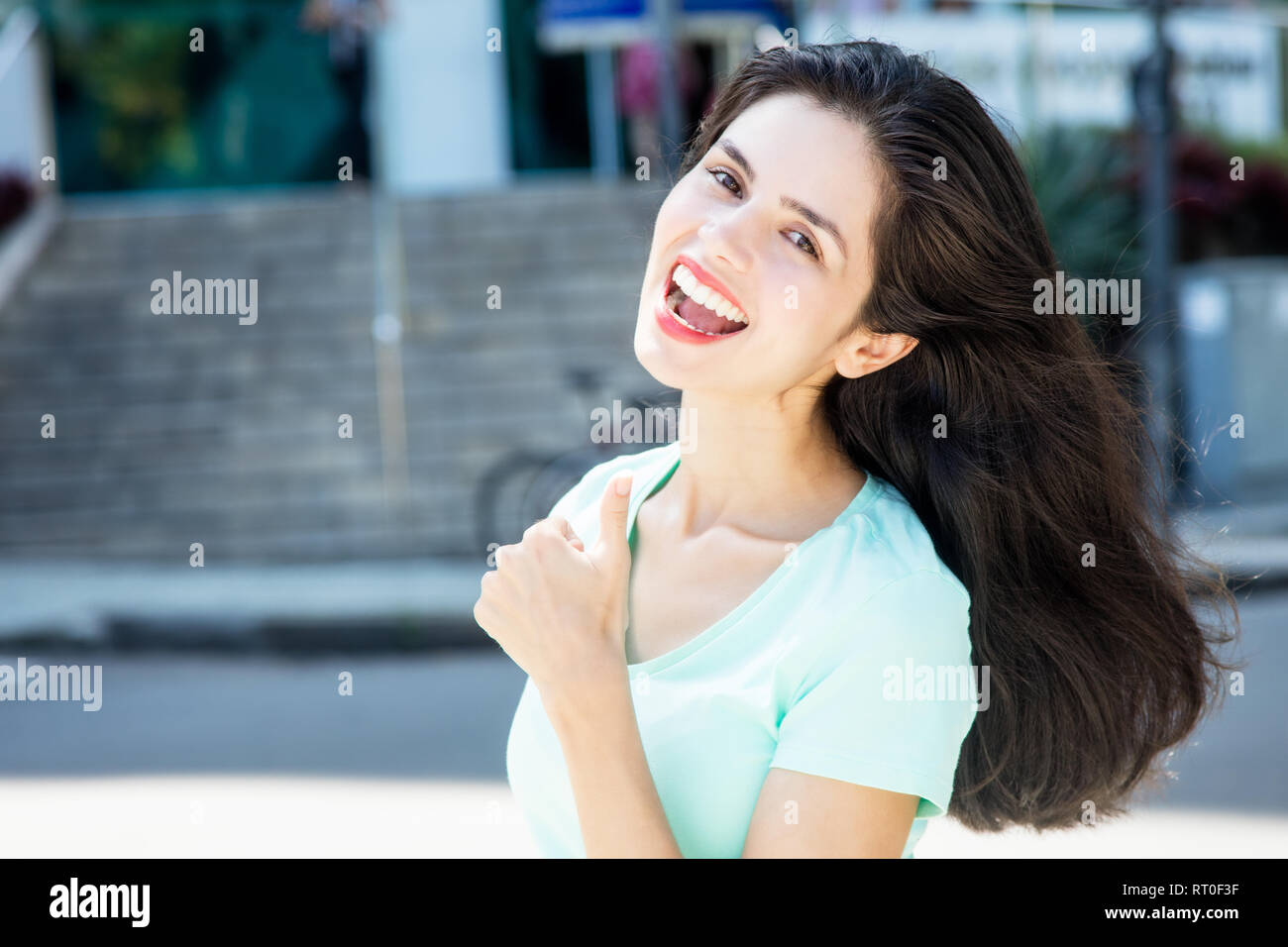 Laughing italian woman showing thumb up outdoors in city with copy ...