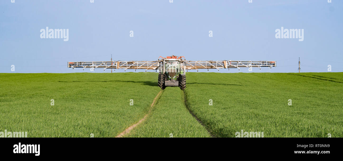 Tractor spraying wheat field with sprayer Stock Photo - Alamy