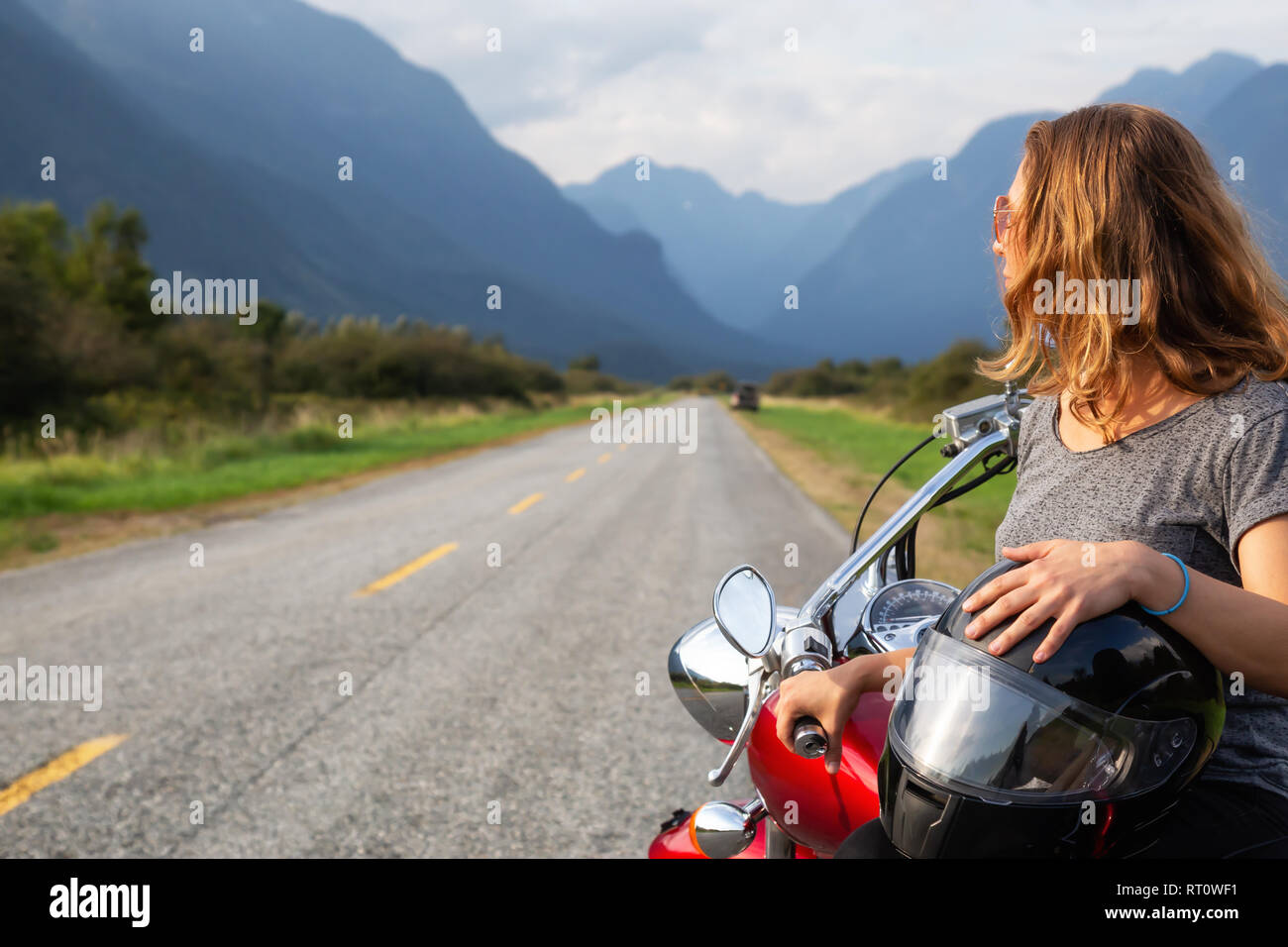 Woman riding a motorcycle on a scenic road surrounded by Canadian ...