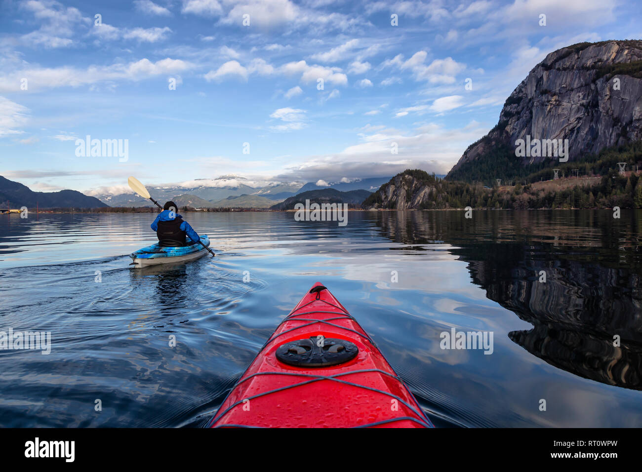Adventurous man kayaking in peaceful water during a cloudy winter day ...