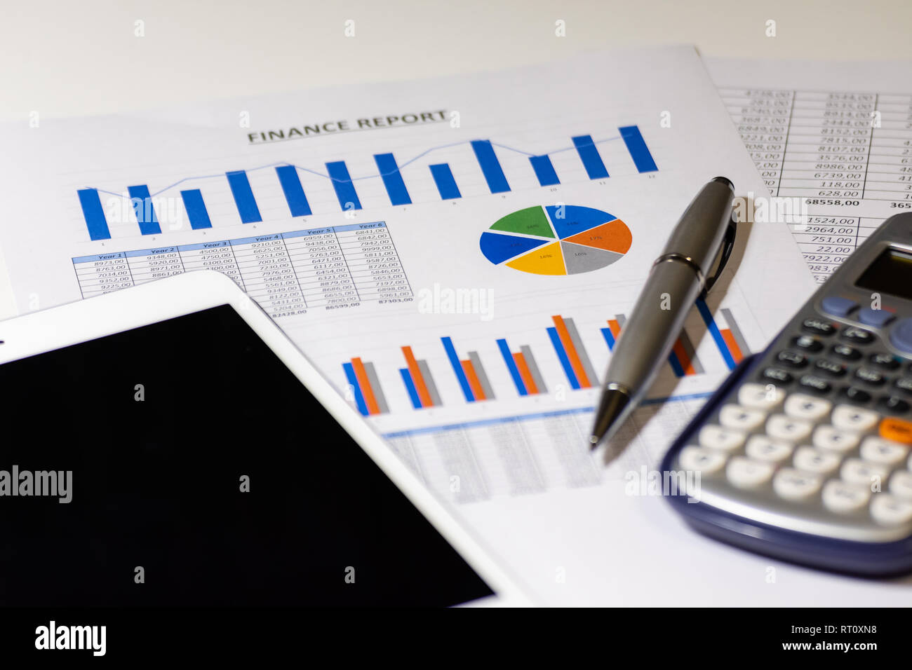 Business diagram on financial report with tablet, pen and calculator ...