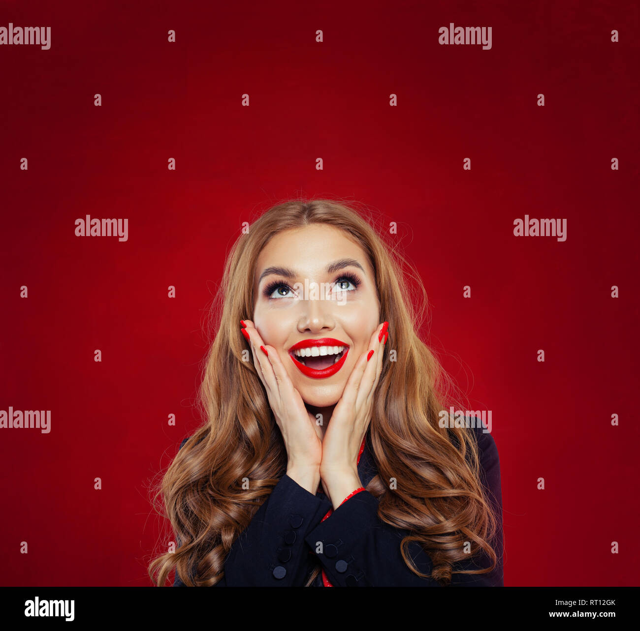 Happy surprised woman looking up on red background. Positive emotions ...