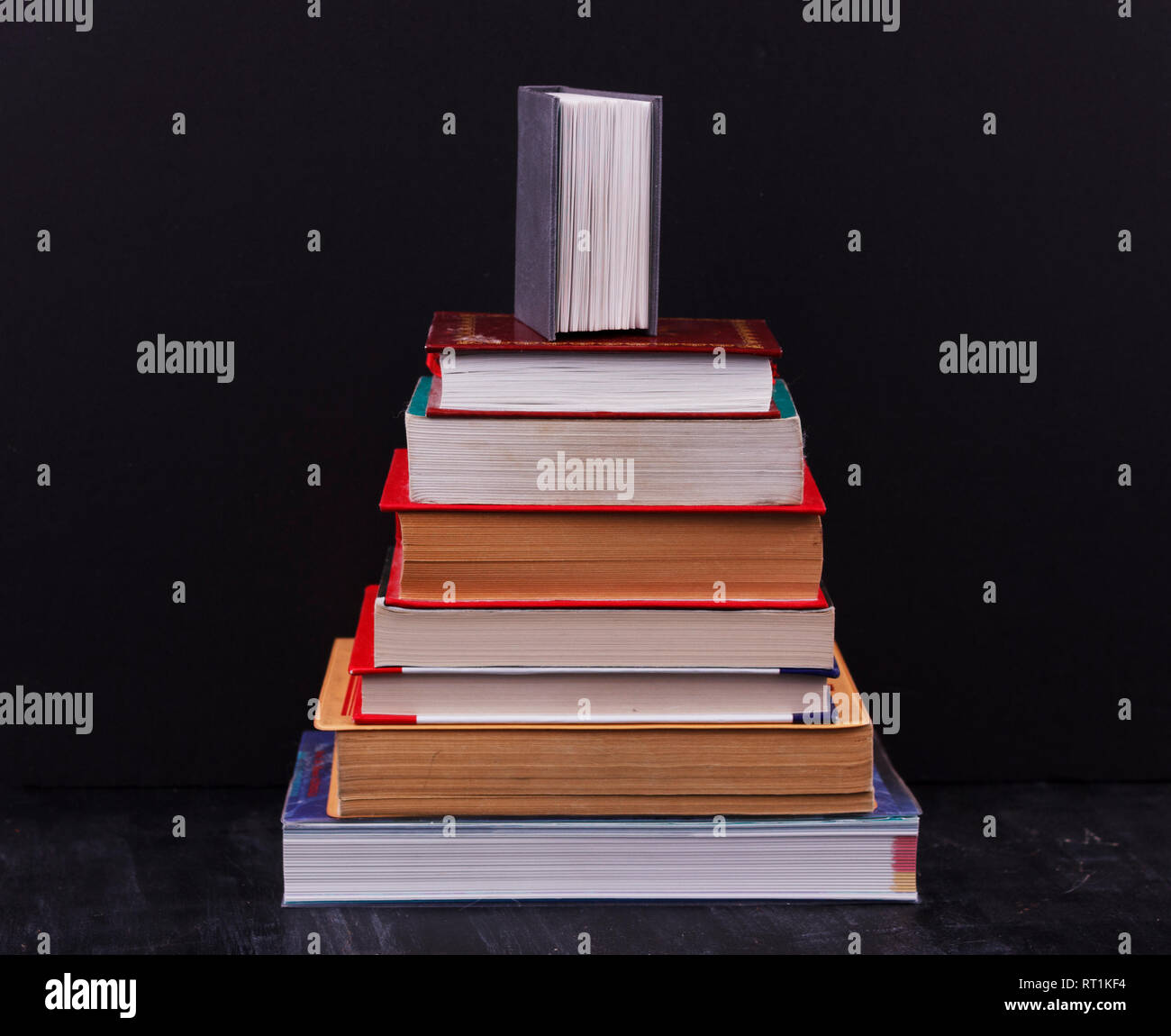 Stack of books on black background with small book on top Stock Photo ...