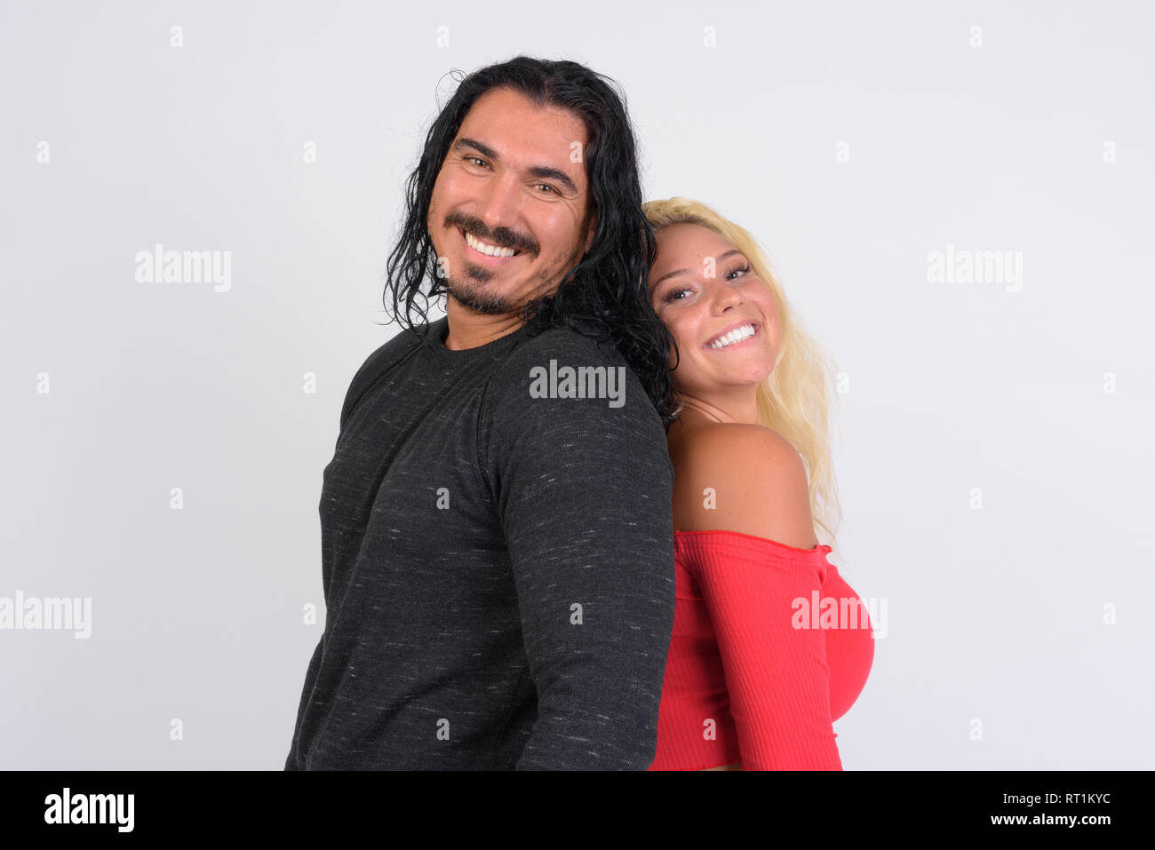 Portrait of happy young couple smiling together back to back Stock ...