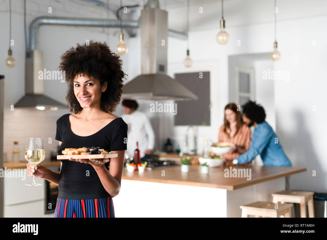 Friends preparing dinner party in the kitchen, woman serving starters ...