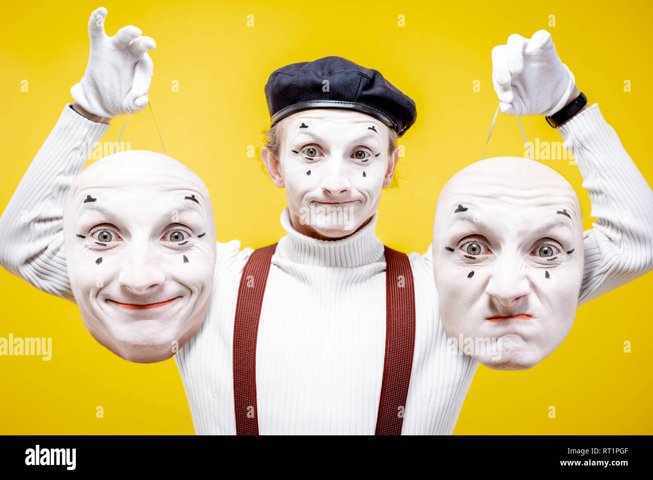 Portrait of a pantoomime holding two facial masks with different ...