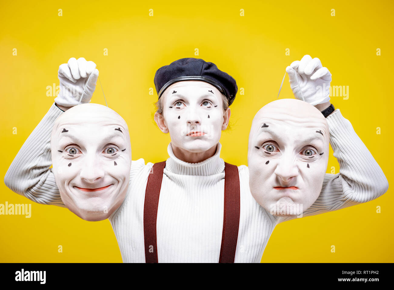 Portrait of a pantoomime holding two facial masks with different ...
